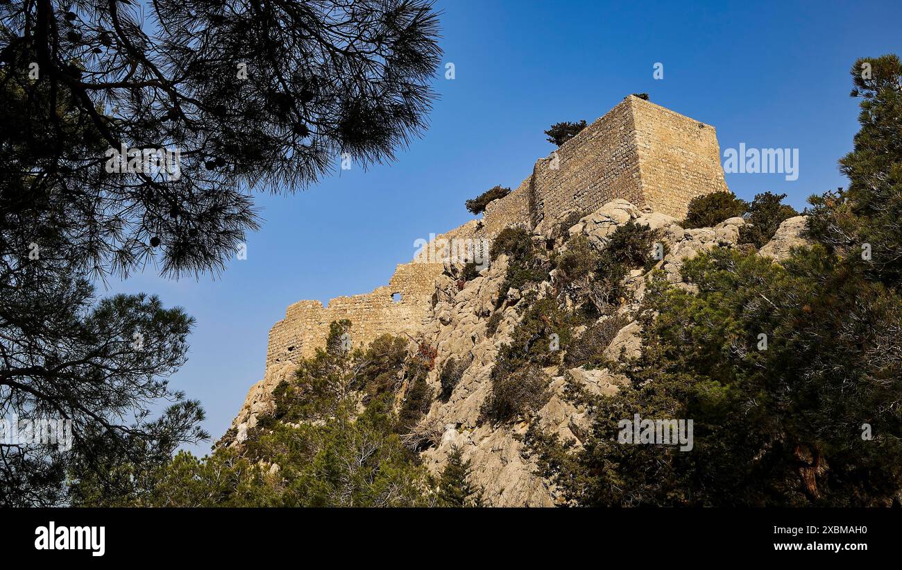 Medieval castle on a rocky hill surrounded by trees and ruins under a ...