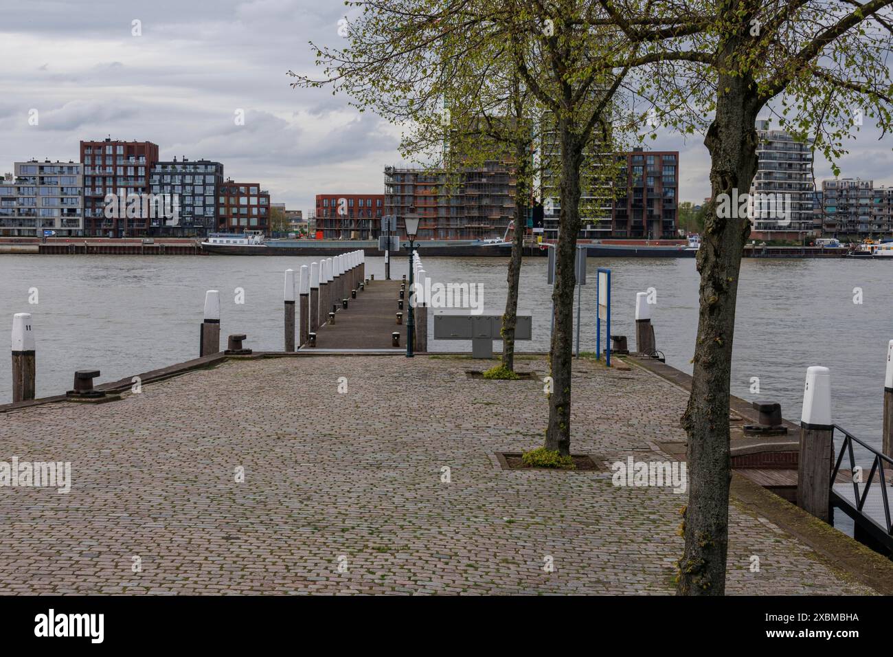 Urban scene with a dock on the river, lined with trees and modern ...