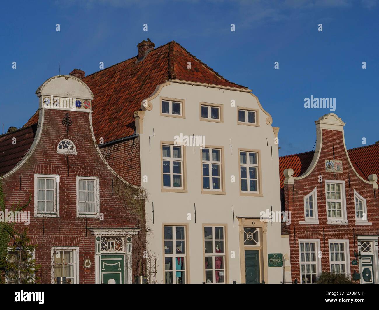 Three historic houses with ornate facades and gables under a clear sky ...