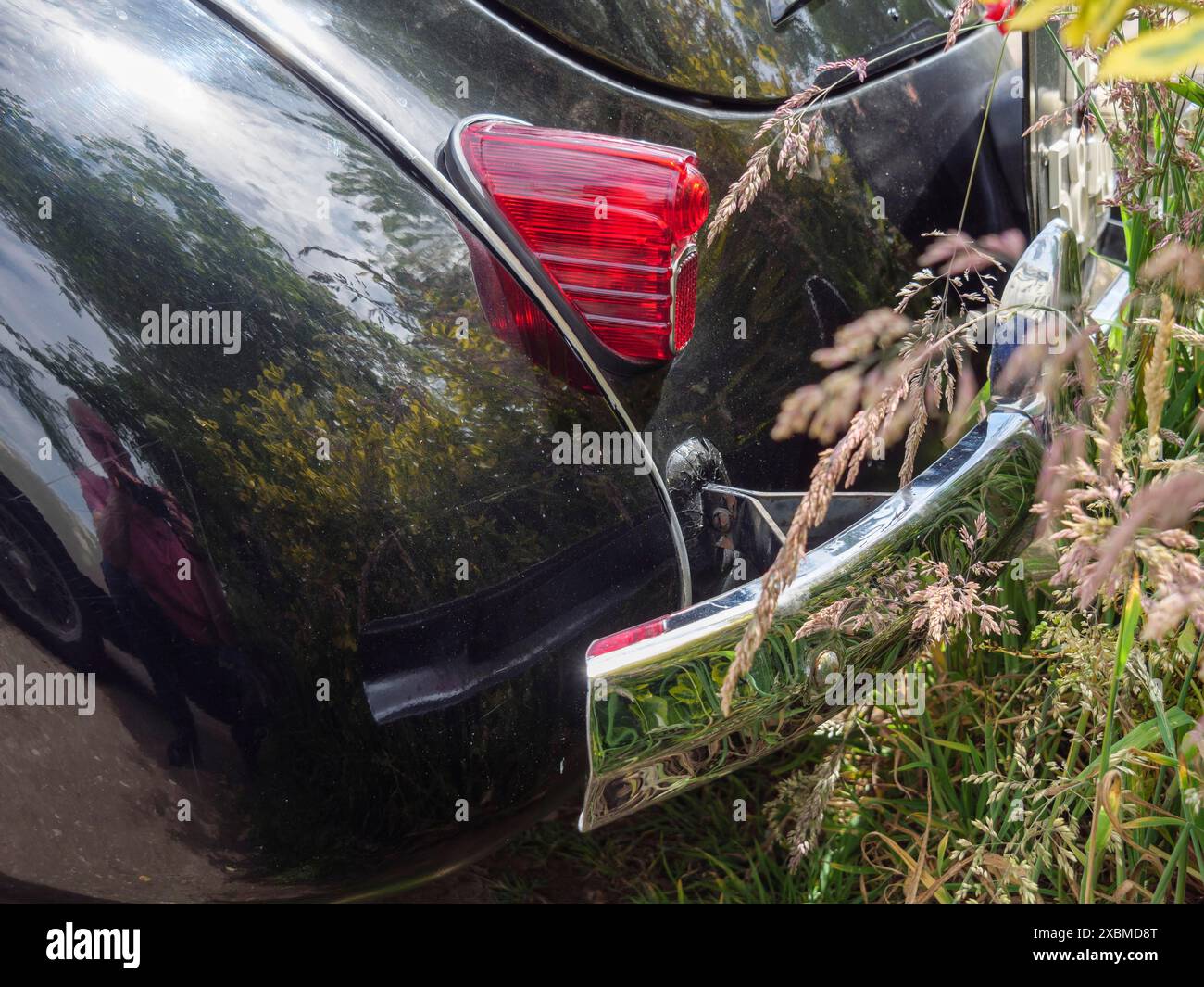Rear view of a black vintage car, showing the tail light and the chrome ...