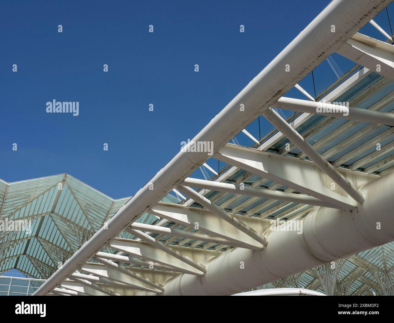 Modern structure with white steel beams and glass roof against a clear ...