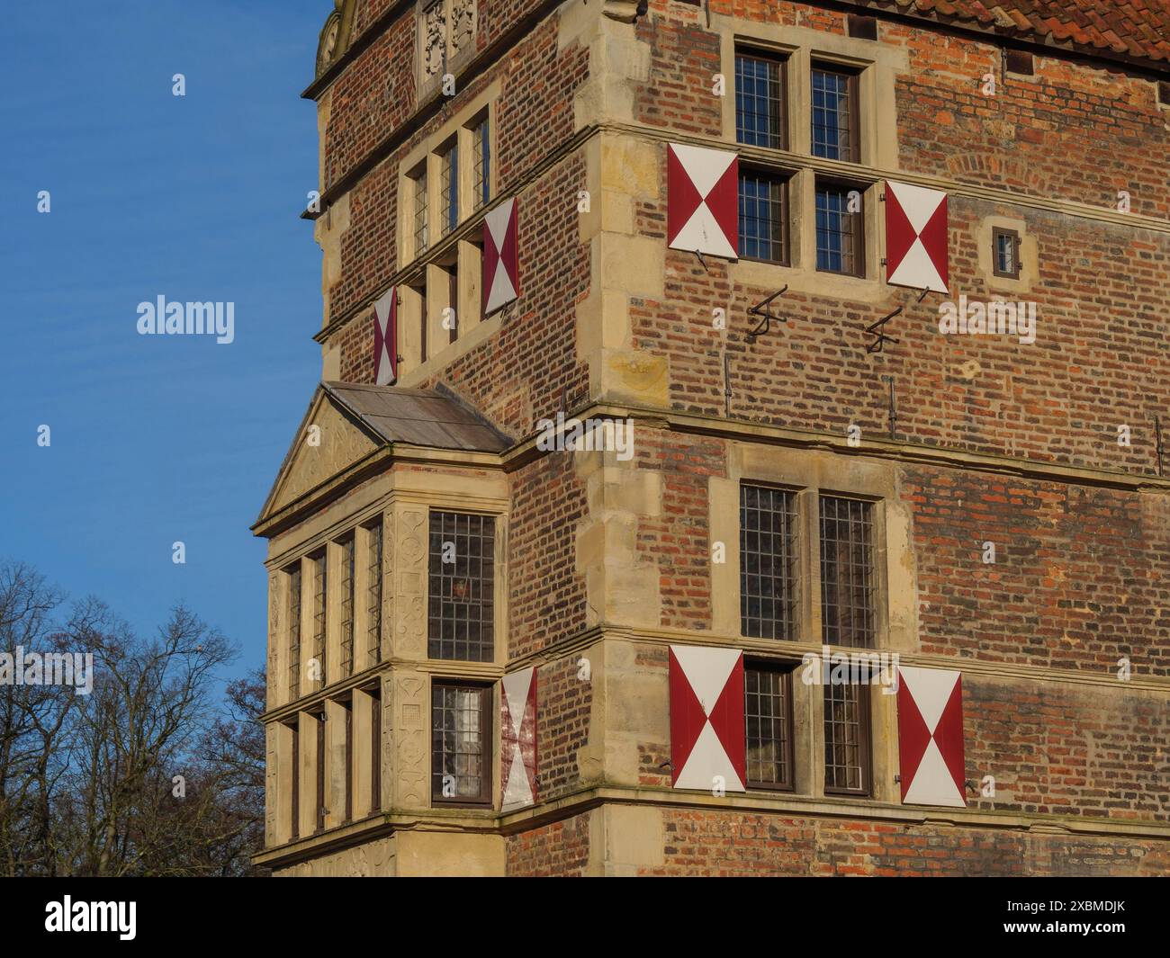 Detail of a historic castle with red and white shutters and a small ...