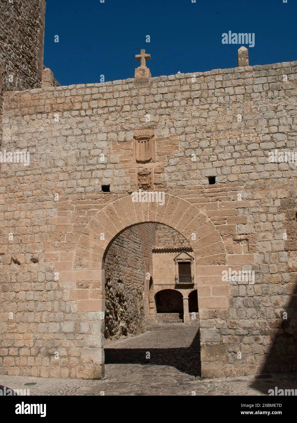 A sandstone arch in a medieval castle complex under a clear sky, ibiza ...