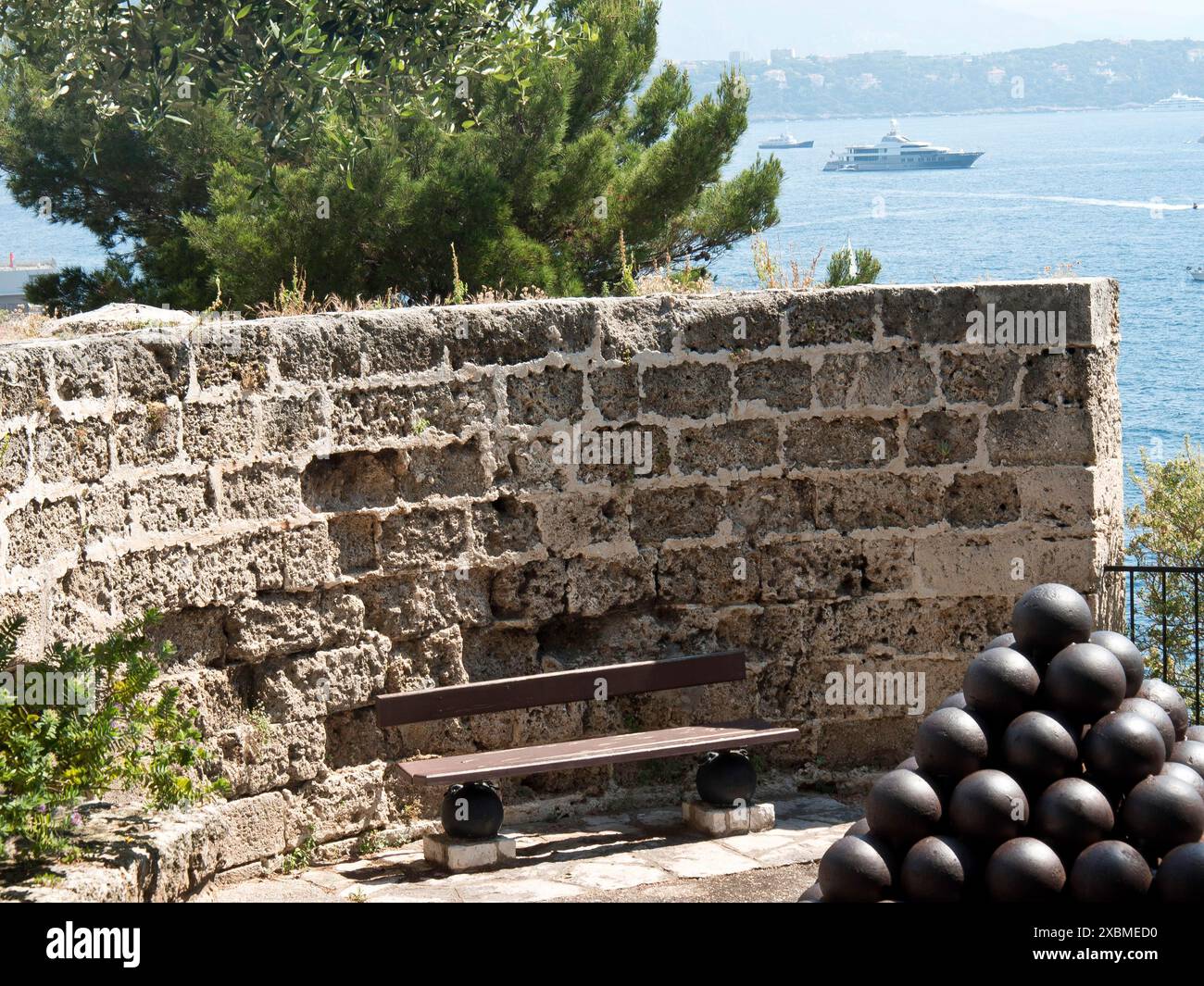 A stone bench with a view of the sea and boats, surrounded by a natural ...