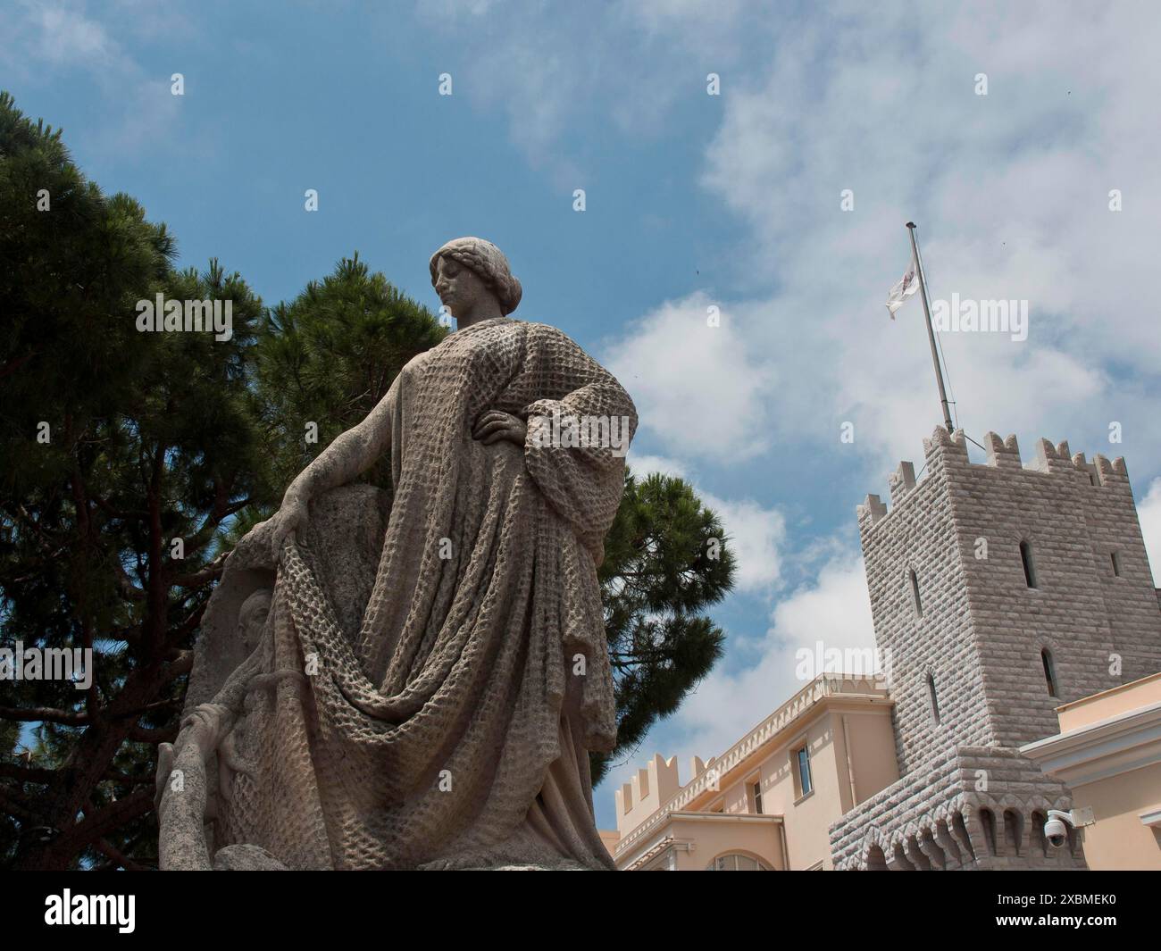 A large stone statue in front of a historic building and tower, with ...