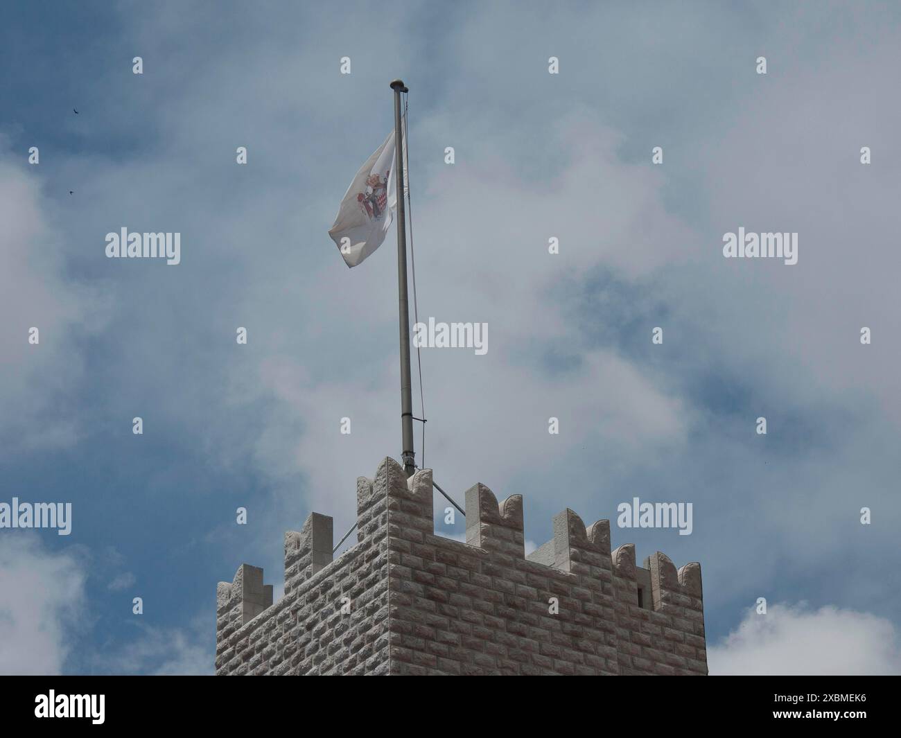 A medieval tower with a waving flag against a cloudy sky, monte carlo ...