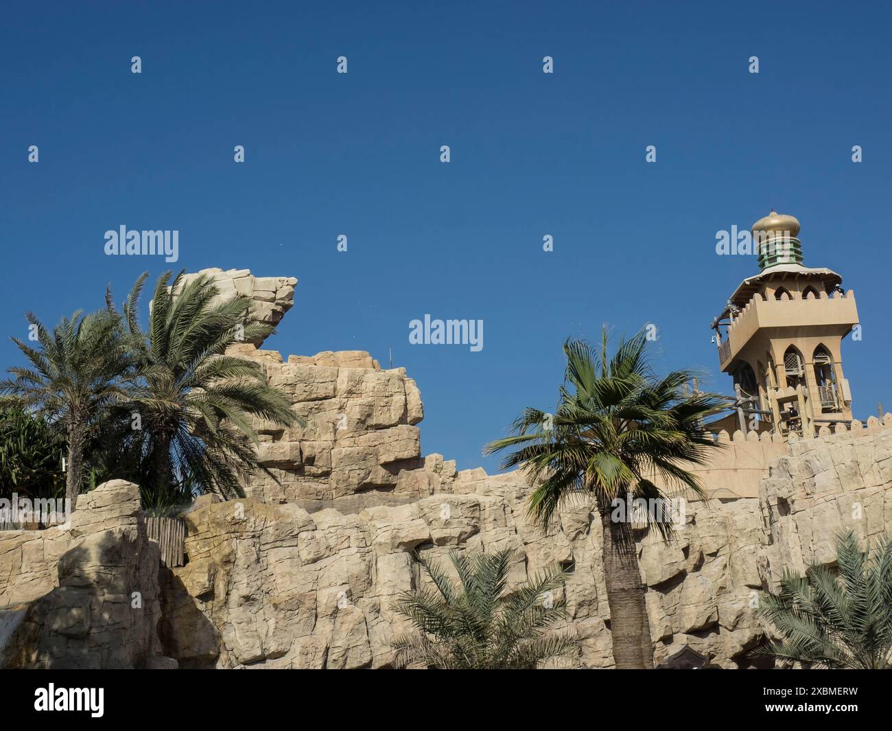 Traditionally designed buildings with palm trees and rock formations ...