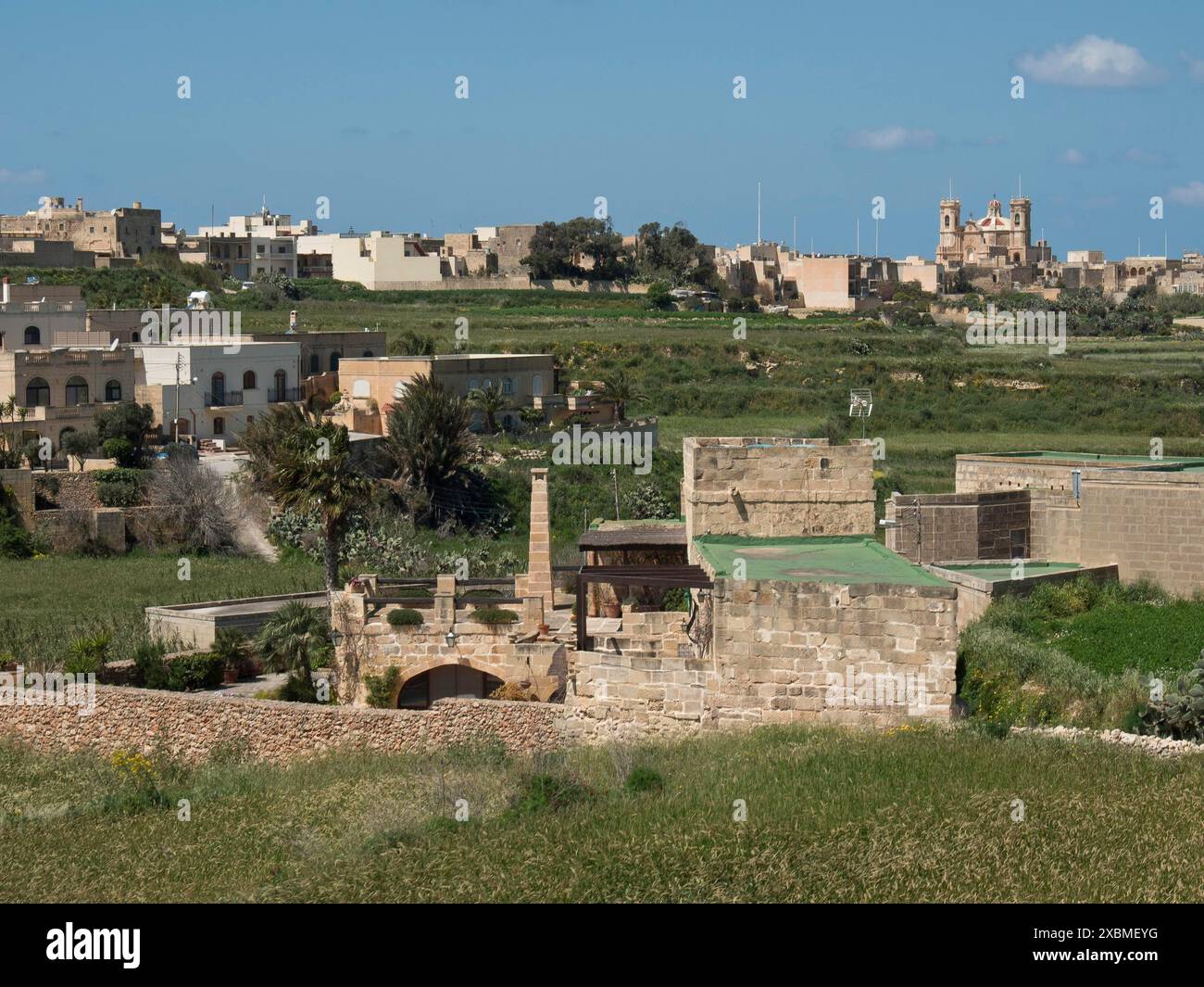 Rural village with traditional buildings and green fields under a clear ...