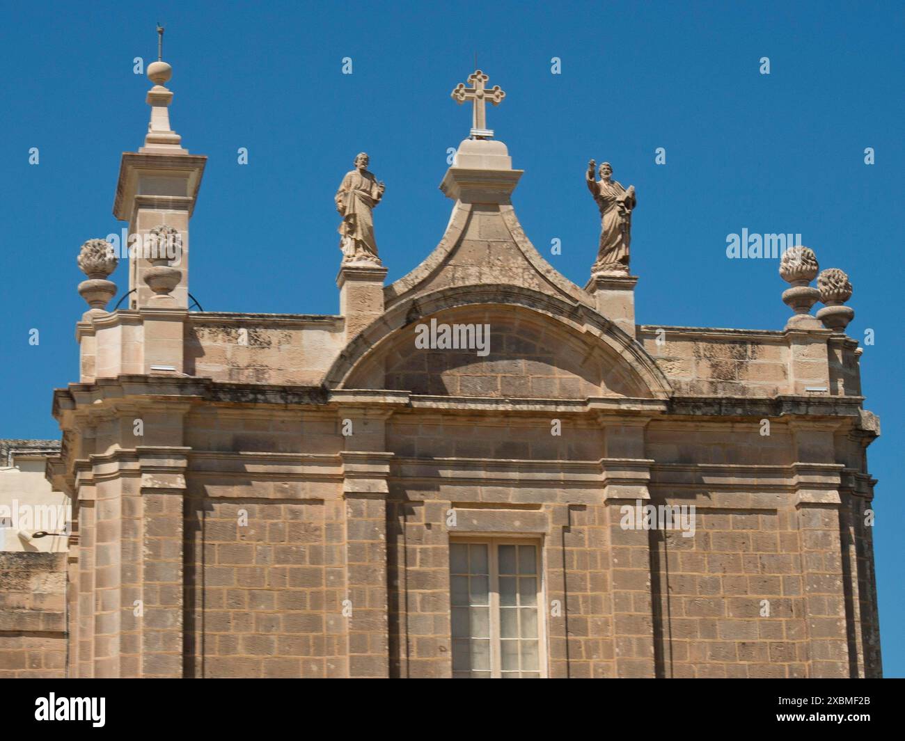 Historic church facade with several statues on the roof and a cross ...