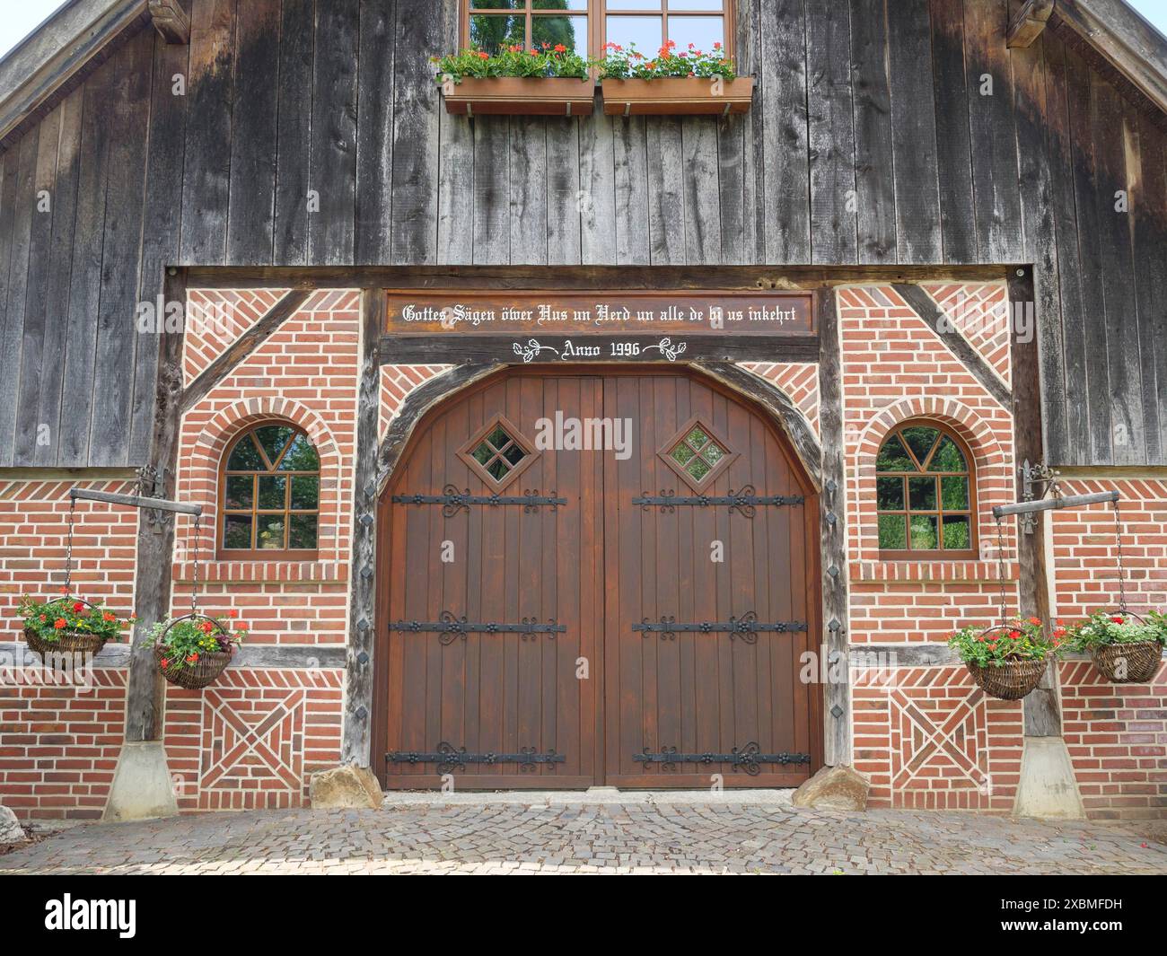 Large barn with wooden and brick elements and planter boxes to the left ...