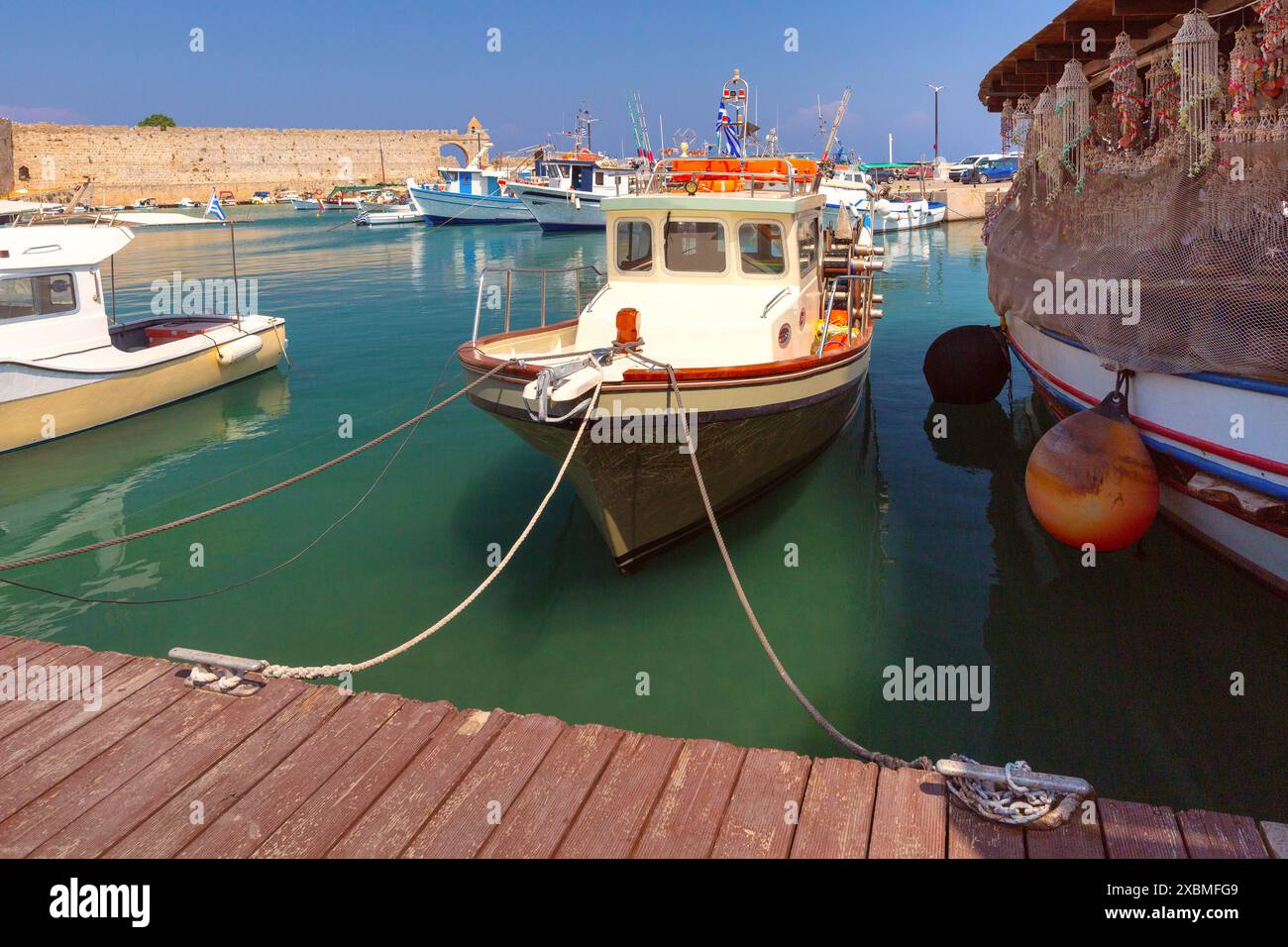 Fishing boats docked in Rhodes Harbor, Greece with medieval walls in ...