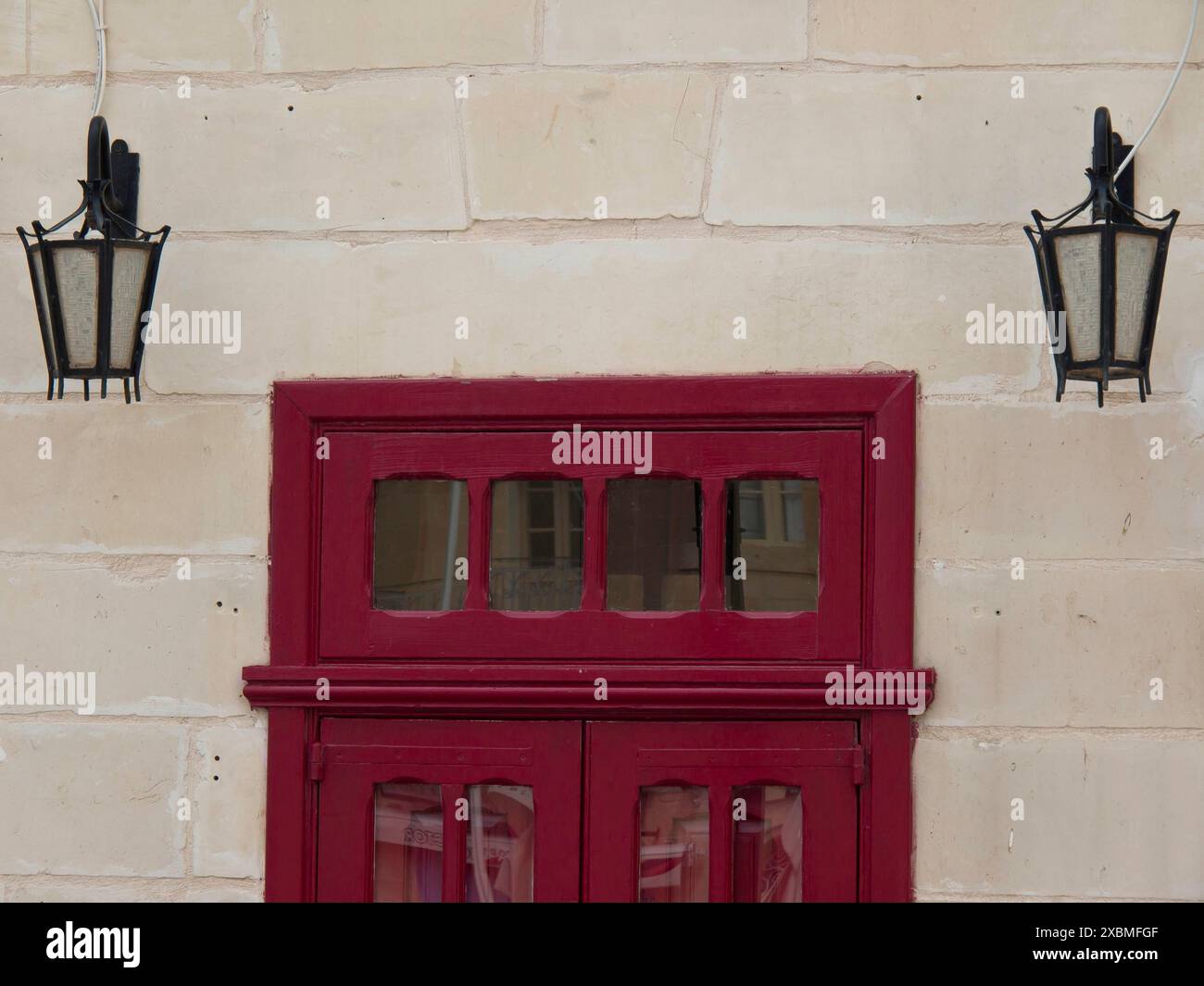 Red door and windows surrounded by beige stone walls with two black ...