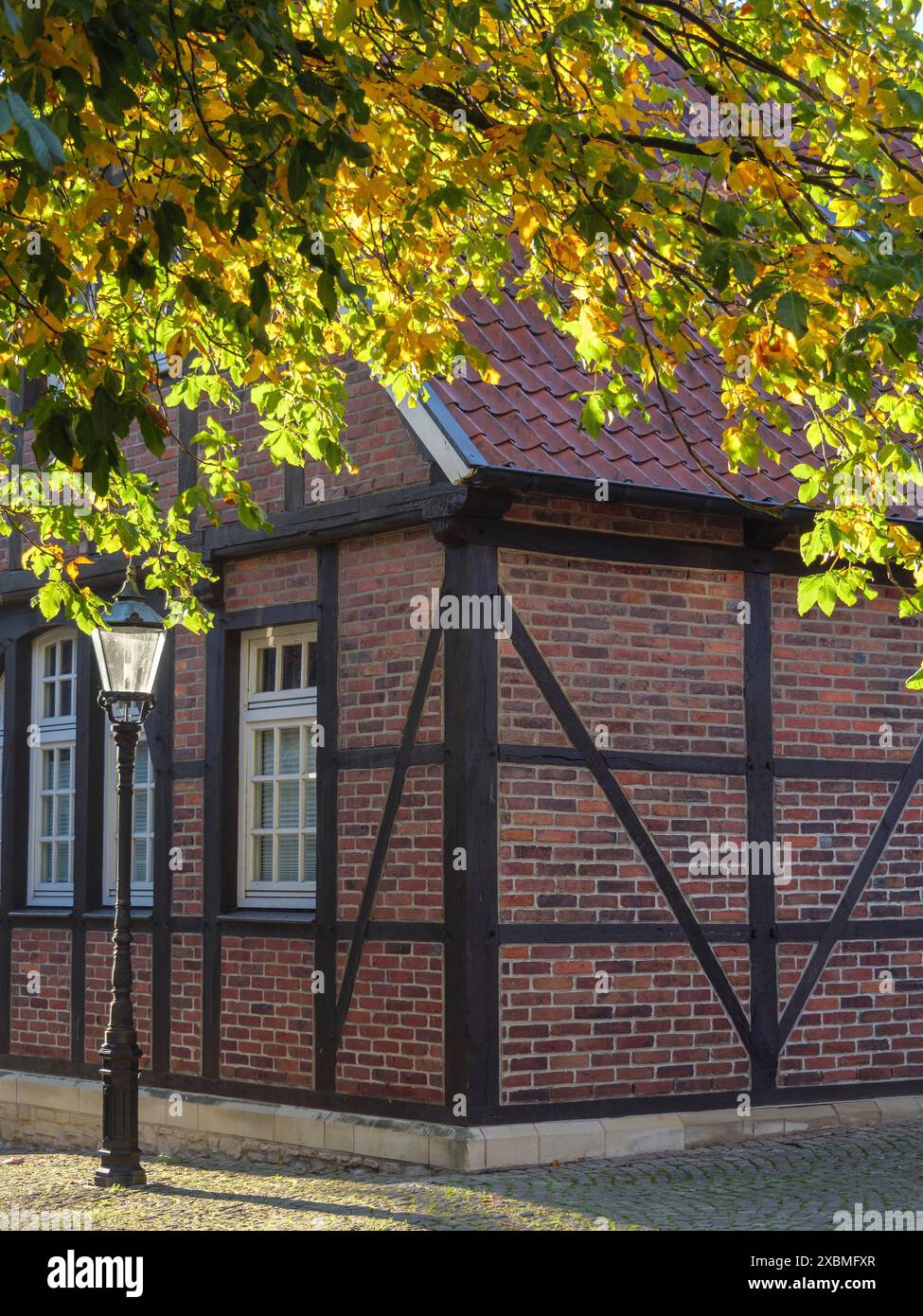 Half-timbered house with brick walls and lantern, surrounded by autumn ...