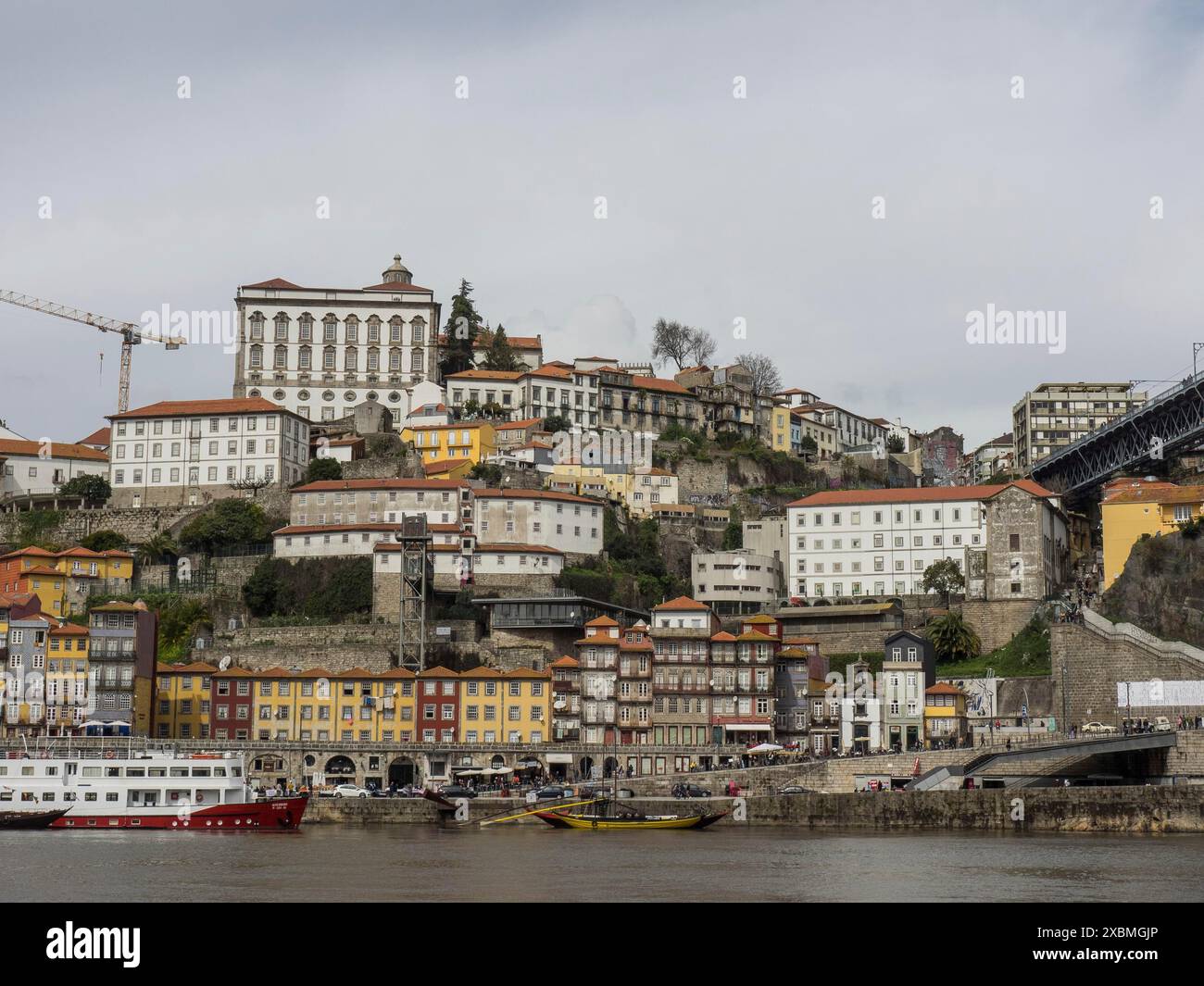 Riverside buildings stretch up the slopes of a hill, with overhanging ...