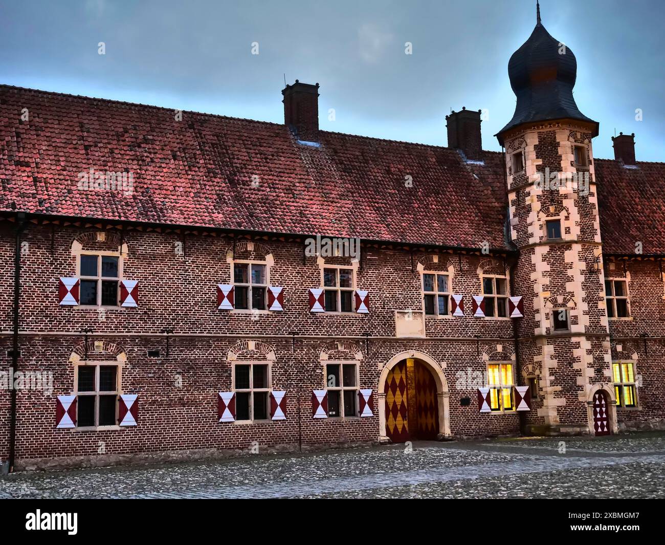 Historic castle with corner tower at dusk, brick facade with many ...