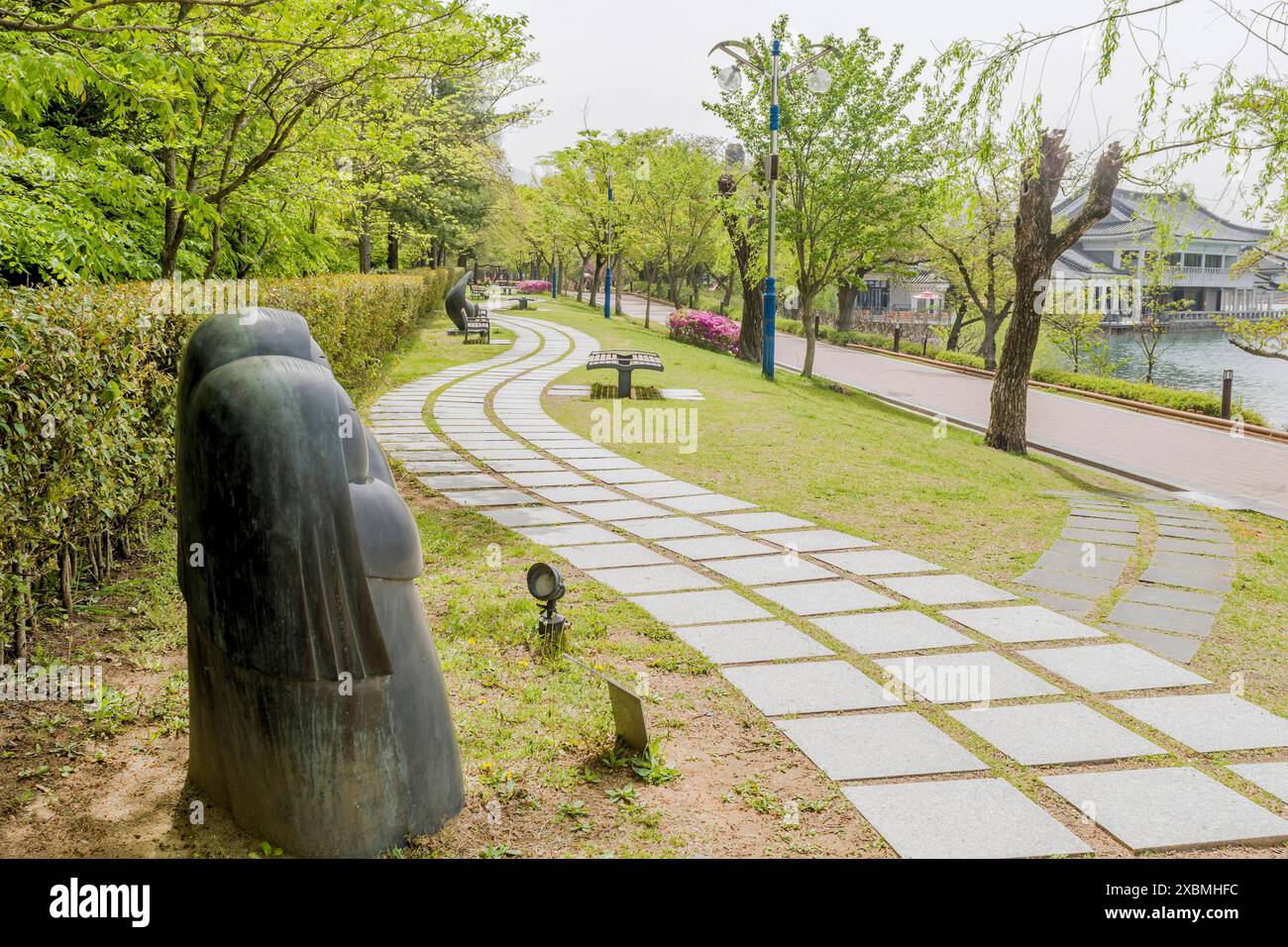 Curved pathway lined with sculptures in a serene park filled with ...