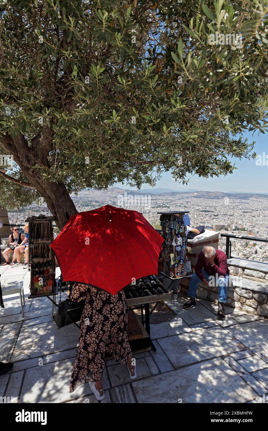 Souvenir stand under a shady olive tree, woman with parasol, panoramic ...
