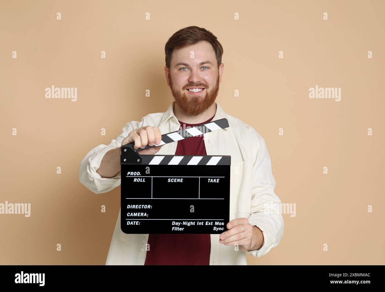 Making movie. Smiling man with clapperboard on beige background Stock ...