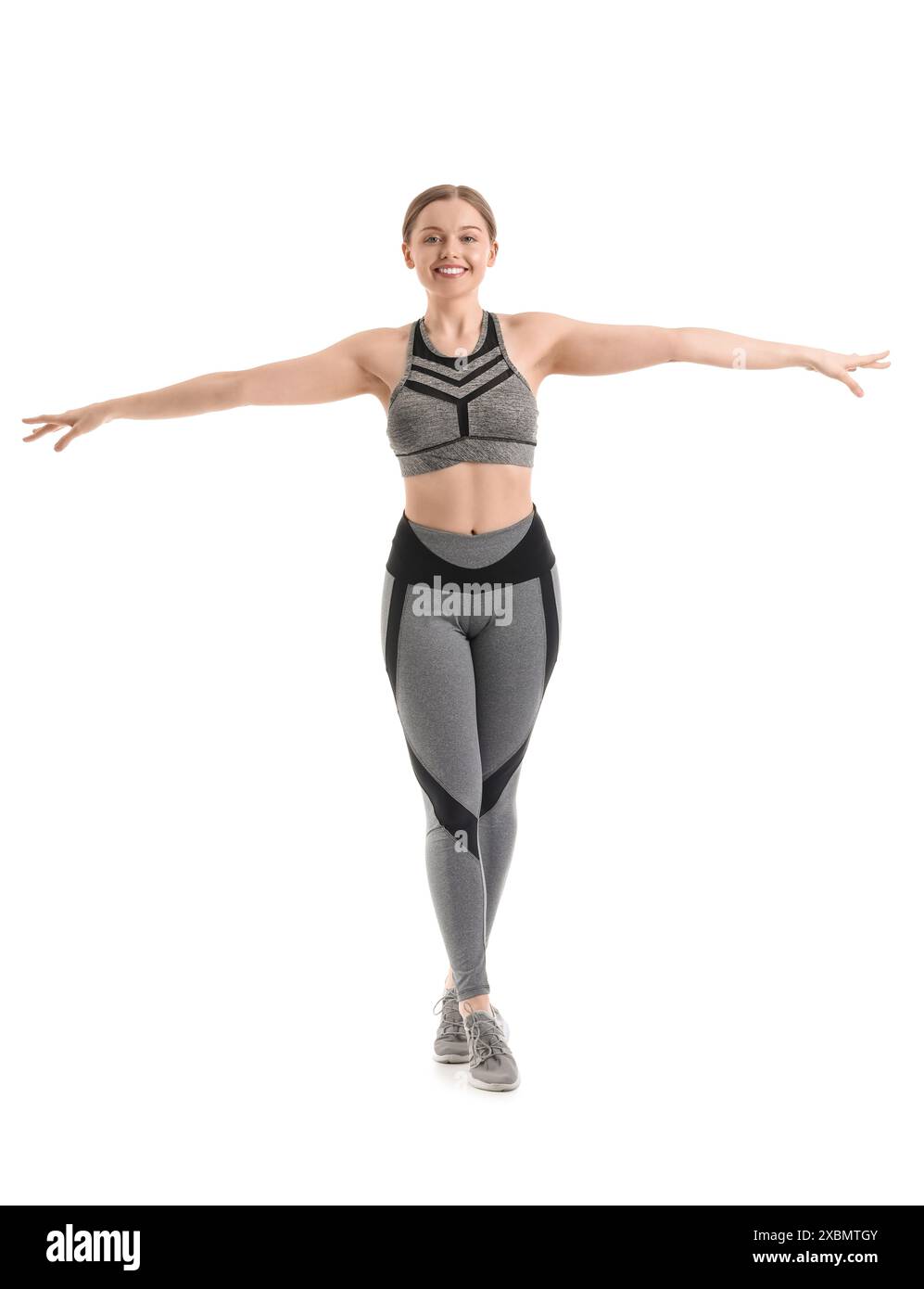 Sporty young woman balancing on white background Stock Photo - Alamy