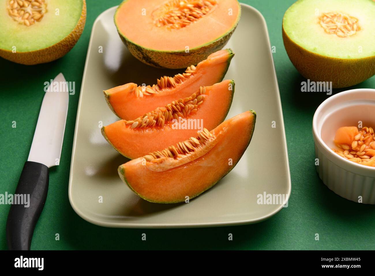 Plate with tasty ripe melons on green background Stock Photo - Alamy