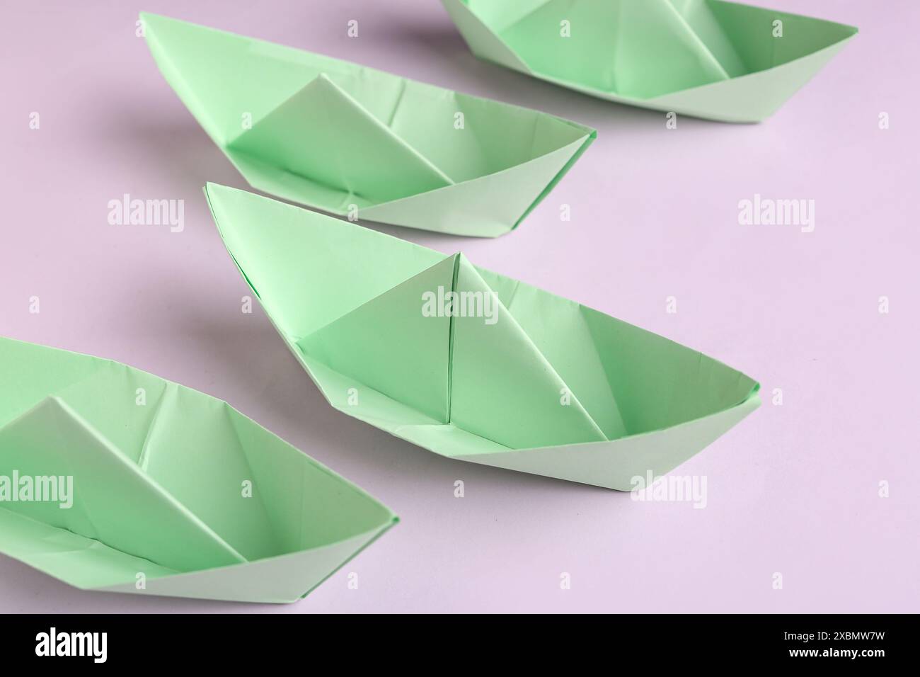 Green origami boats on purple background Stock Photo - Alamy