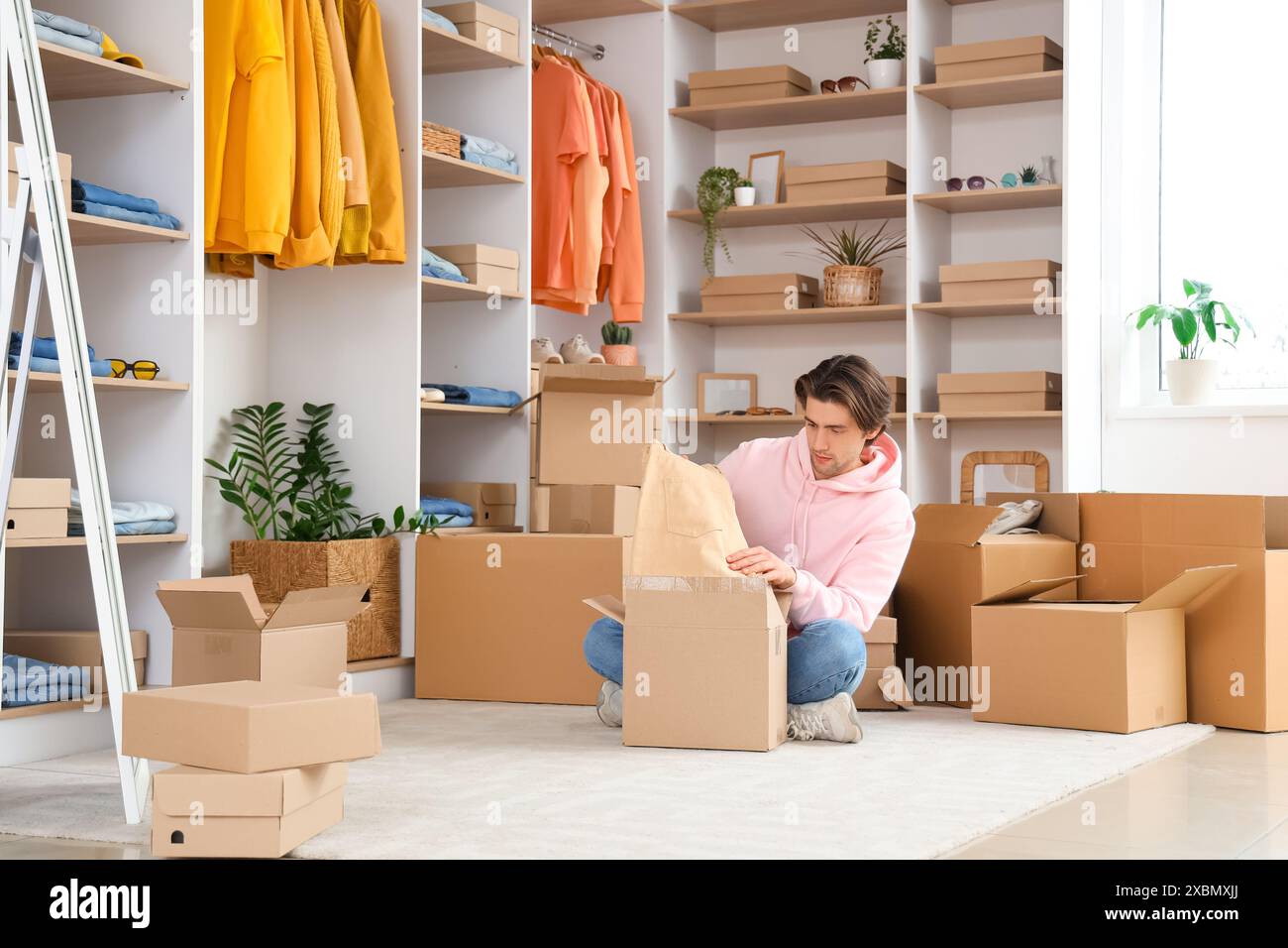 Handsome young man with wardrobe boxes sitting in dressing room Stock ...