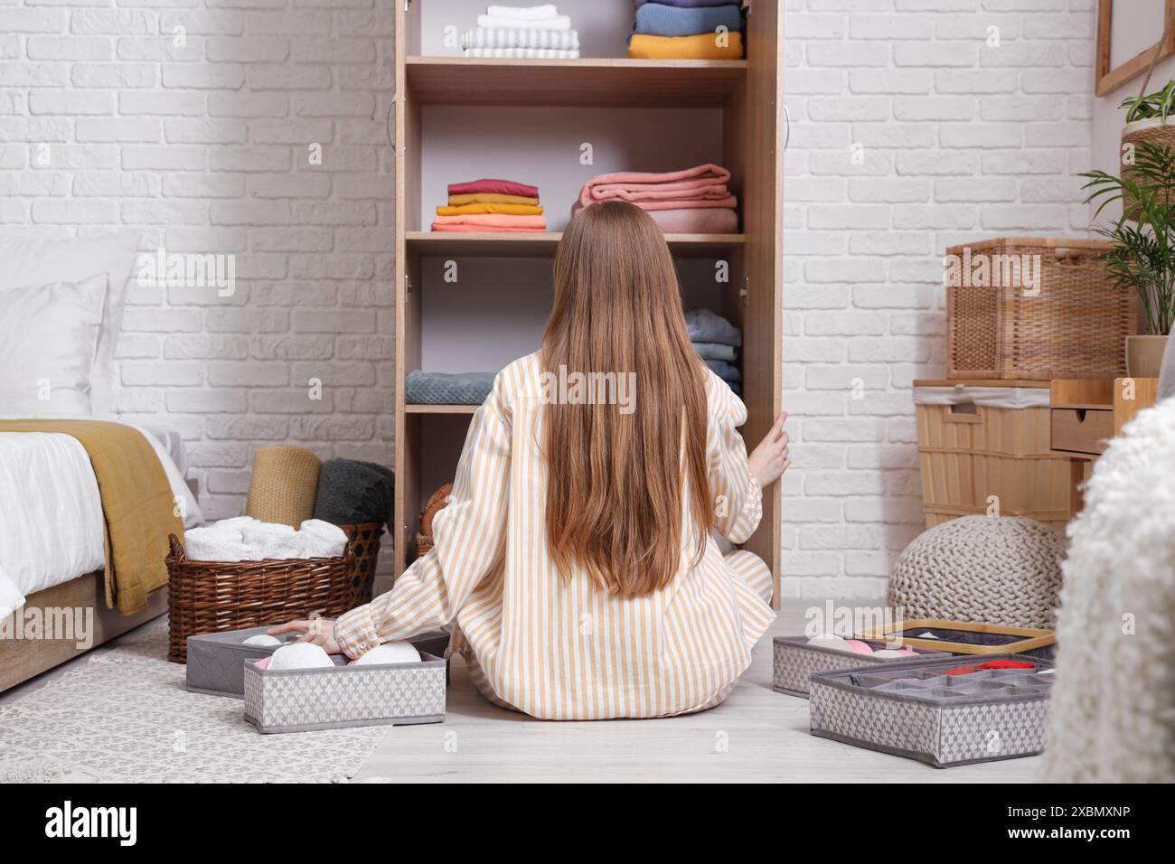 Young woman folding clean clothes in wardrobe Stock Photo - Alamy