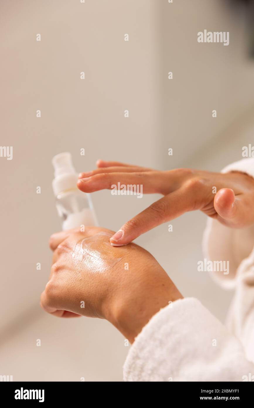 Caucasian woman applying lotion on her hand in soft lighting, copy ...