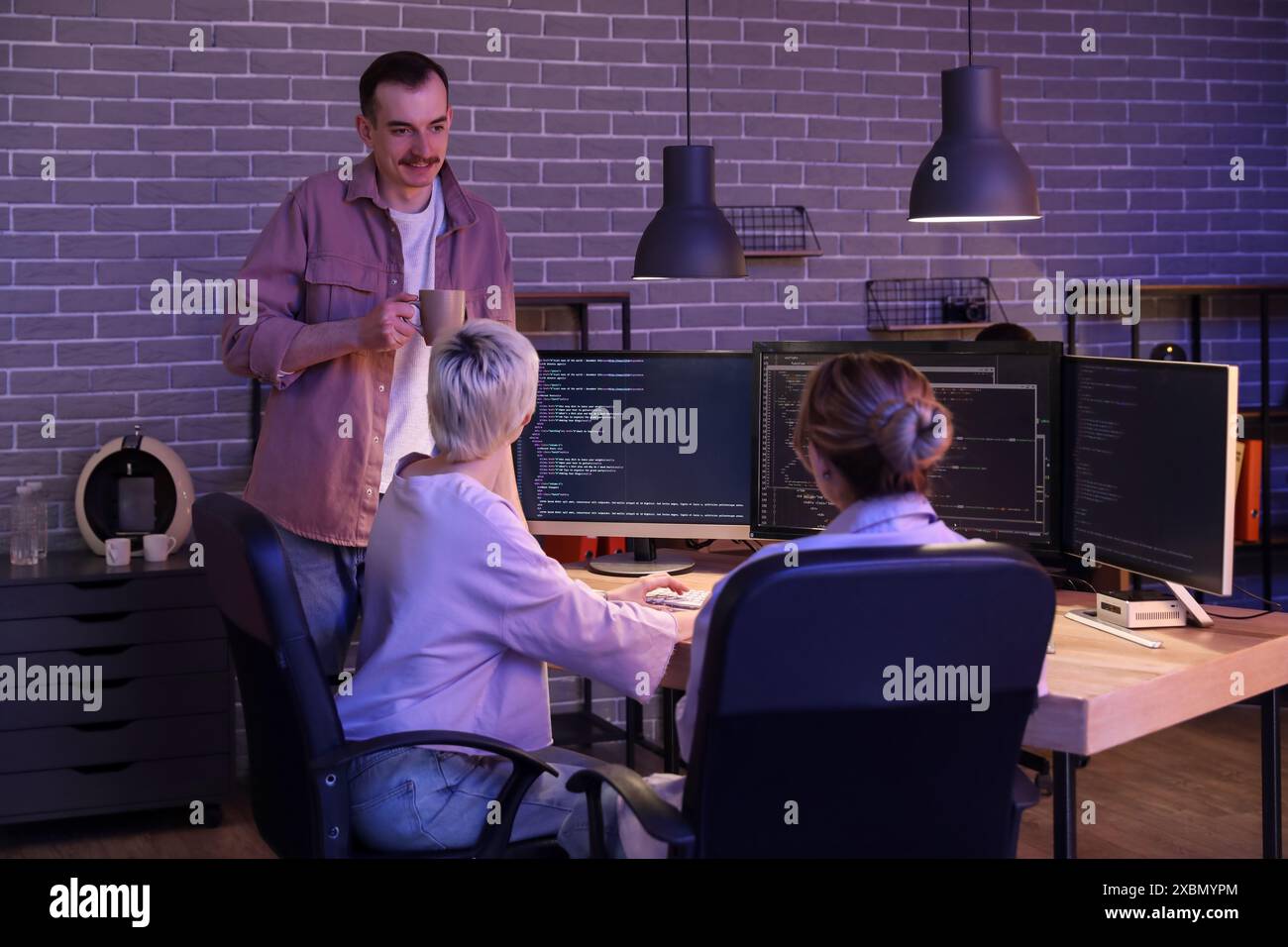 Male programmer with coffee and his colleagues working in office at ...
