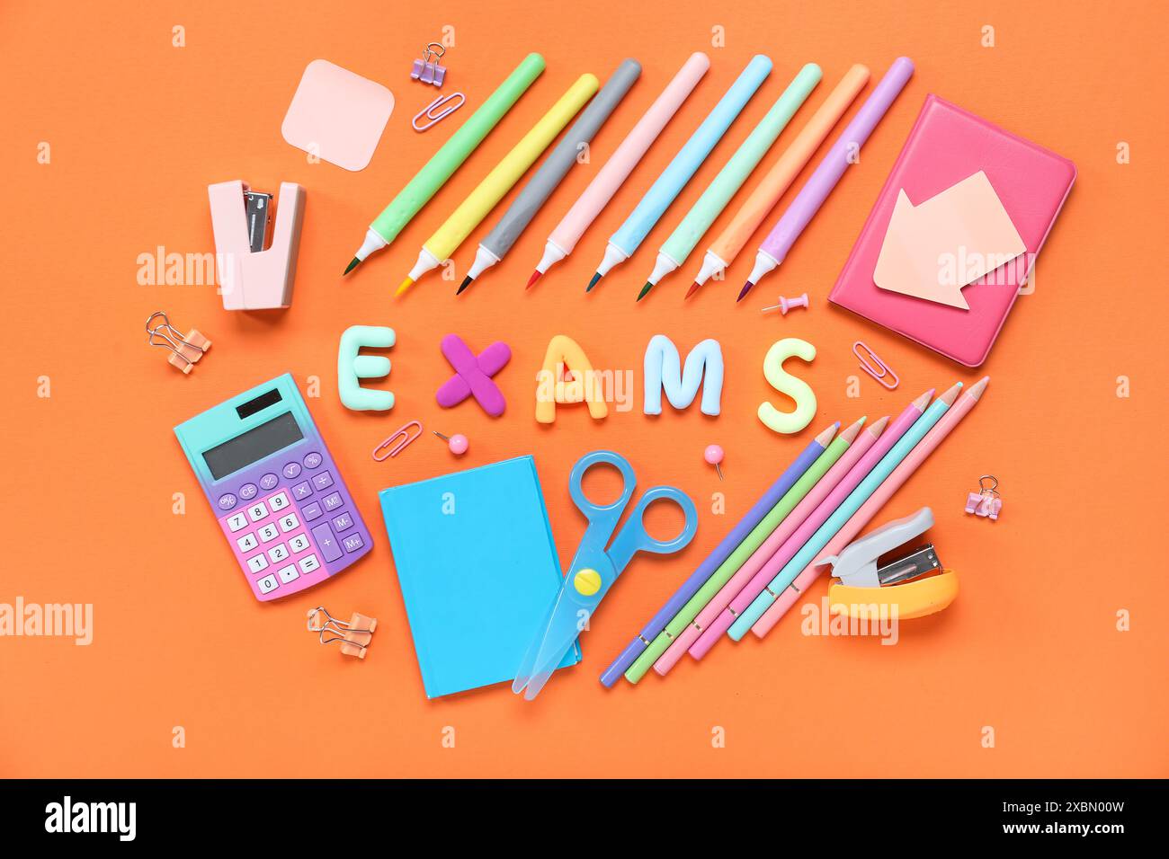 Composition with word EXAMS and colorful stationery on orange ...