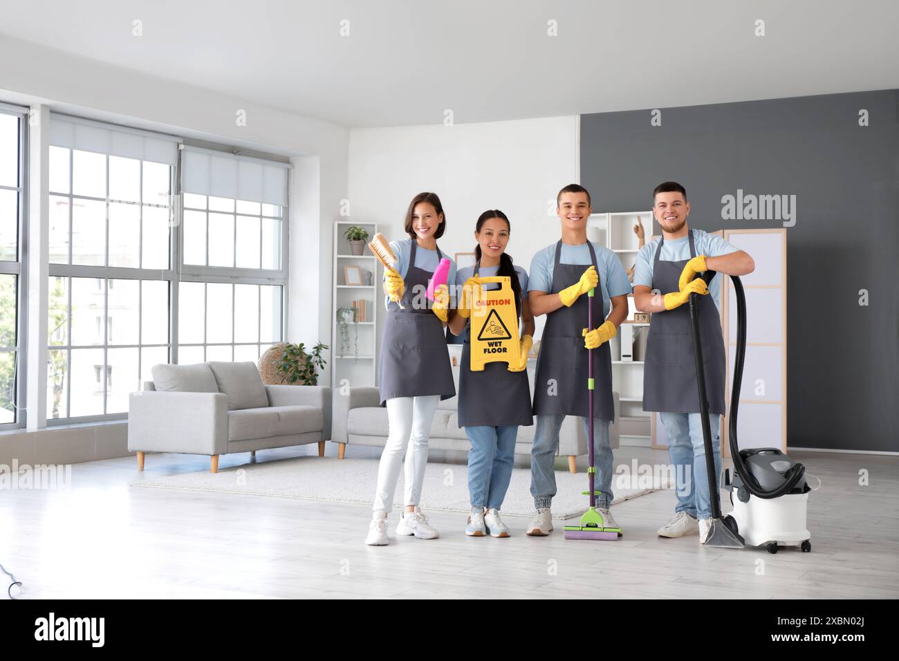 Group of young janitors with cleaning supplies in room Stock Photo - Alamy