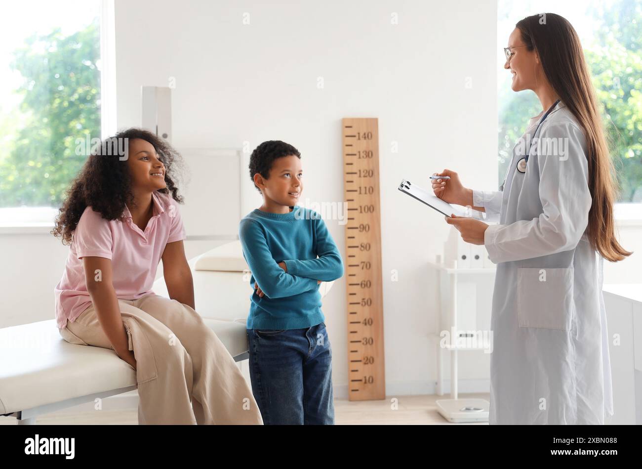 Female pediatrician with little African-American children measuring ...