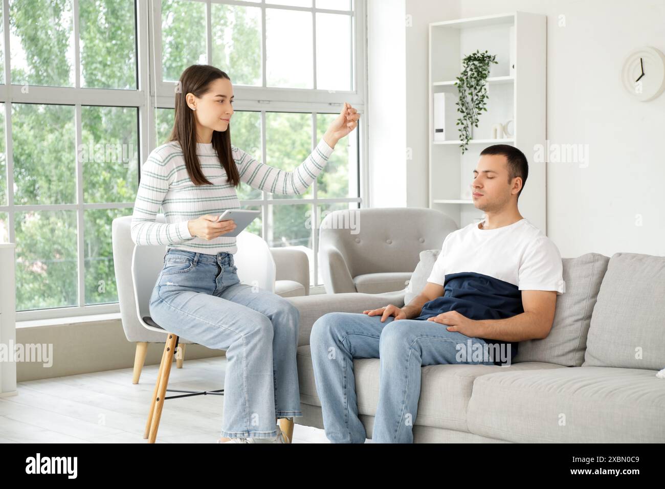 Female psychologist with pendulum hypnotizing young man in office Stock ...