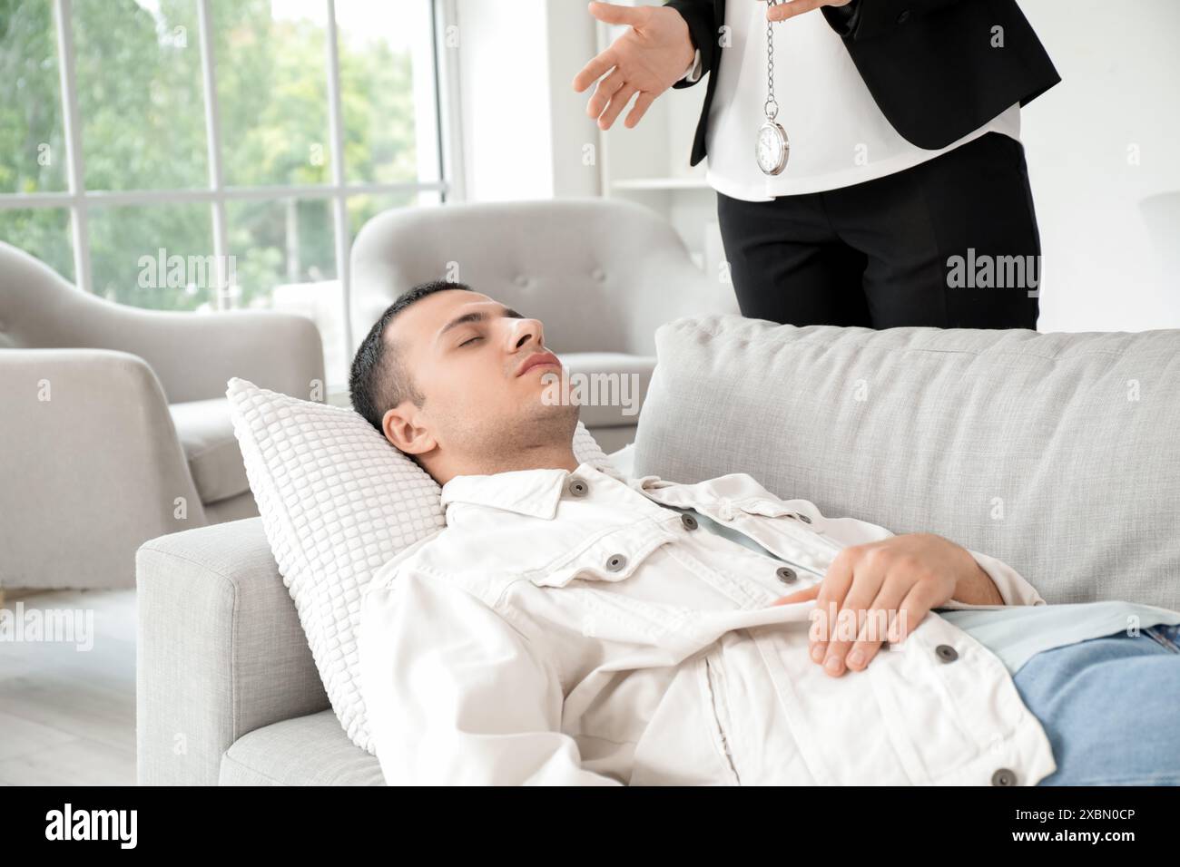 Female psychologist with pocket watch hypnotizing young man in office ...