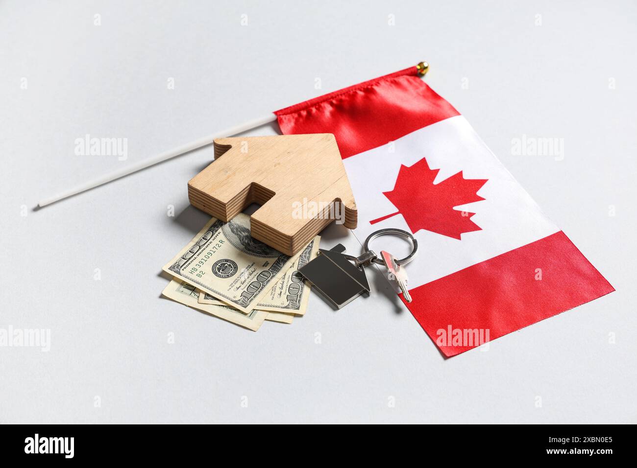 Figure of house, keys, money and Canadian flag on light background ...