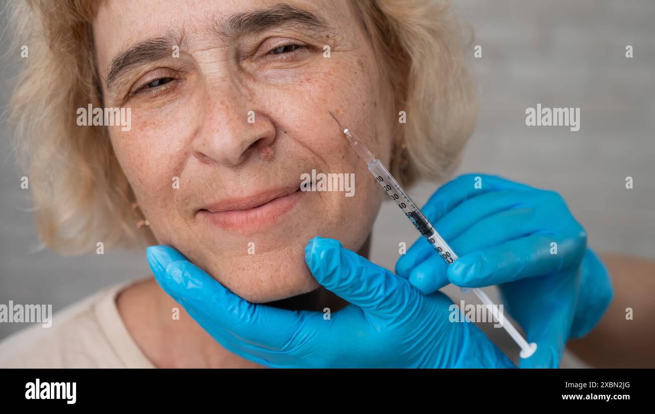 Doctor makes beauty injections in the face of an old caucasian woman ...
