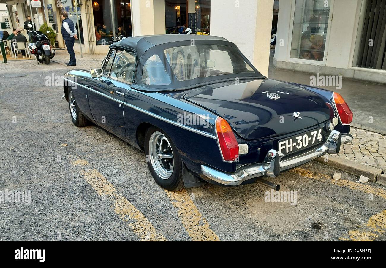 Dark blue 1970-s MG MGB roadster parked by the curbside, back left ...