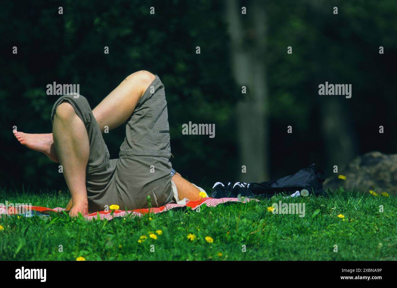 Man laying on grass with legs crossed, English Garden, Munich, Germany ...