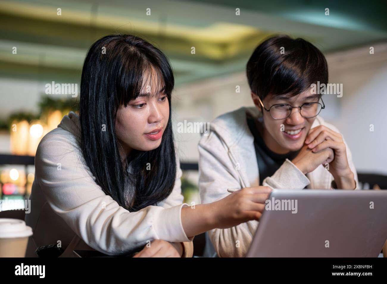 A smart, young Asian female college student is helping her friend with ...