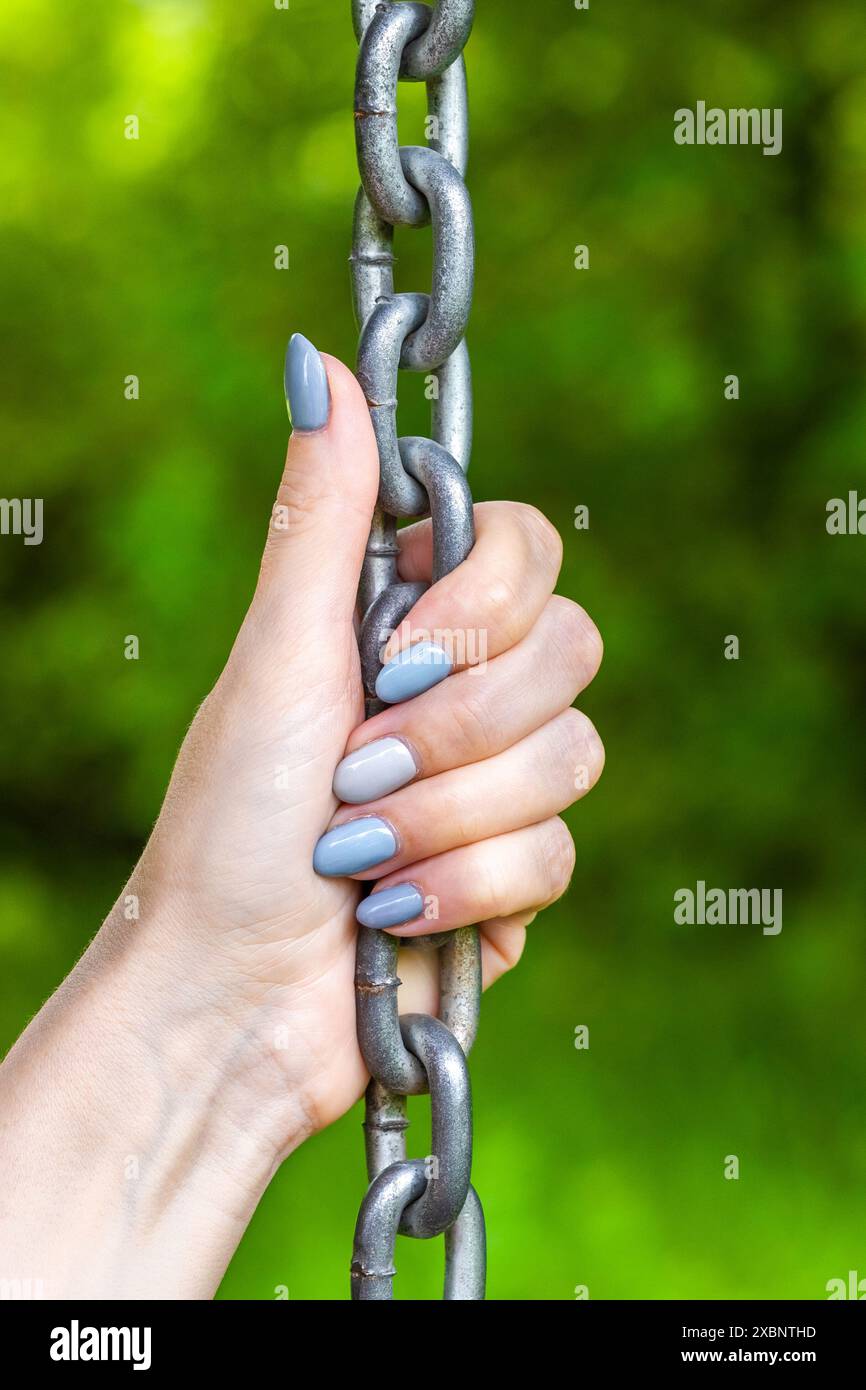 female hand holding a metal chain, close-up. hand holding a metal chain ...