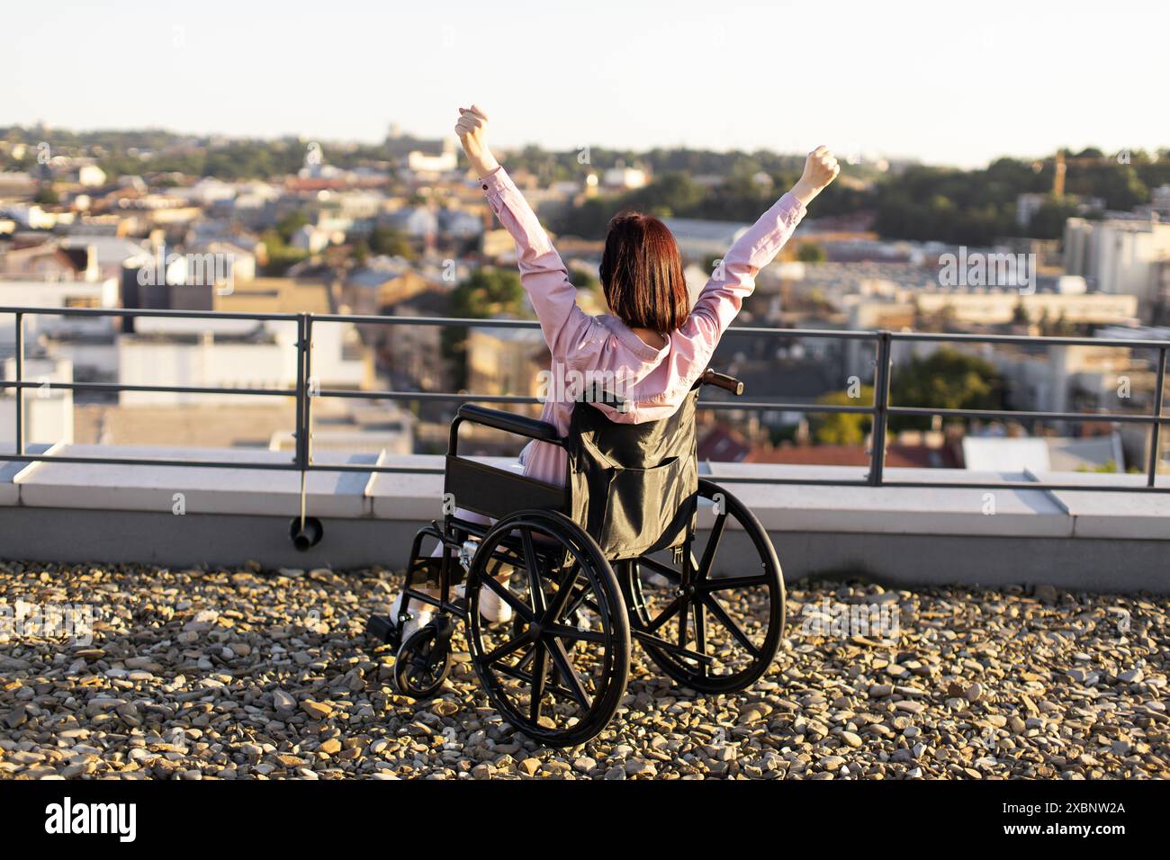 Woman in wheelchair raising arms on rooftop overlooking cityscape Stock ...