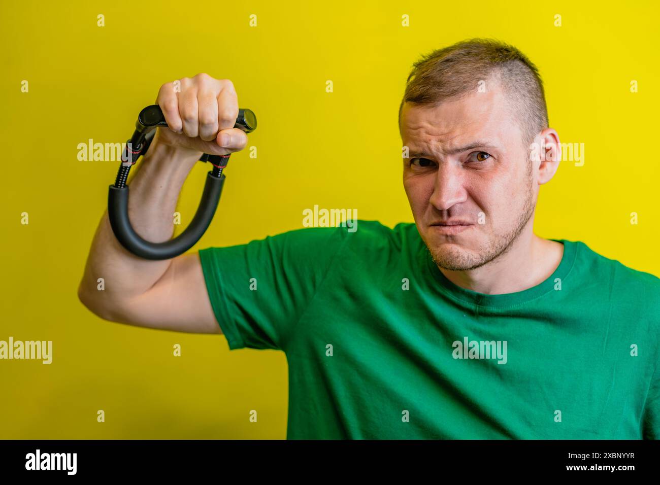 Determined Man Flexing Bicep With Hand Grip Exerciser Against Yellow ...