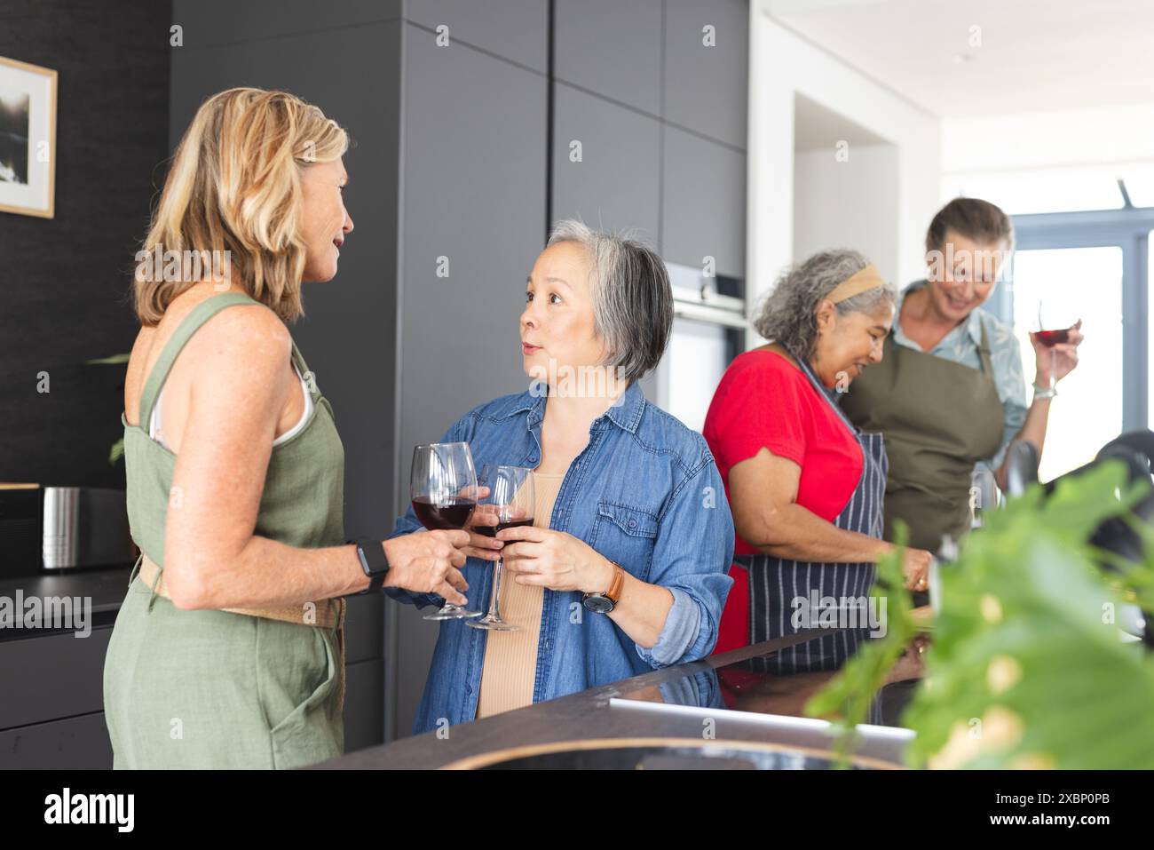Diverse group of mature women enjoying wine and conversation in modern ...