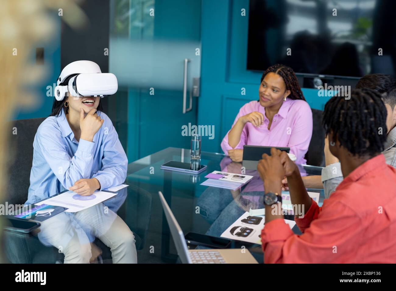 Business team collaborate in a startup, one using a VR headset ...