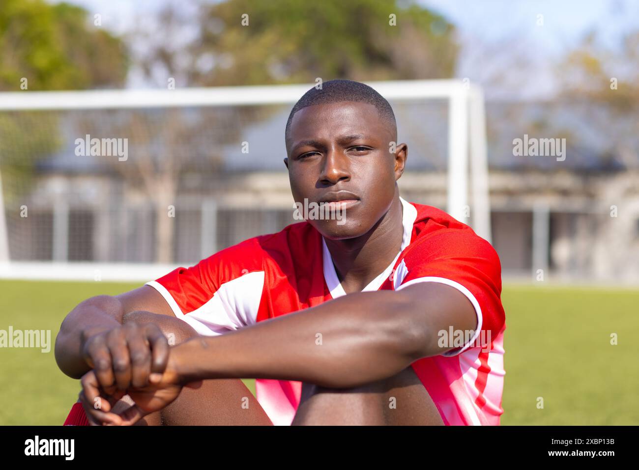 Young African American soccer player sitting on soccer field, looking ...