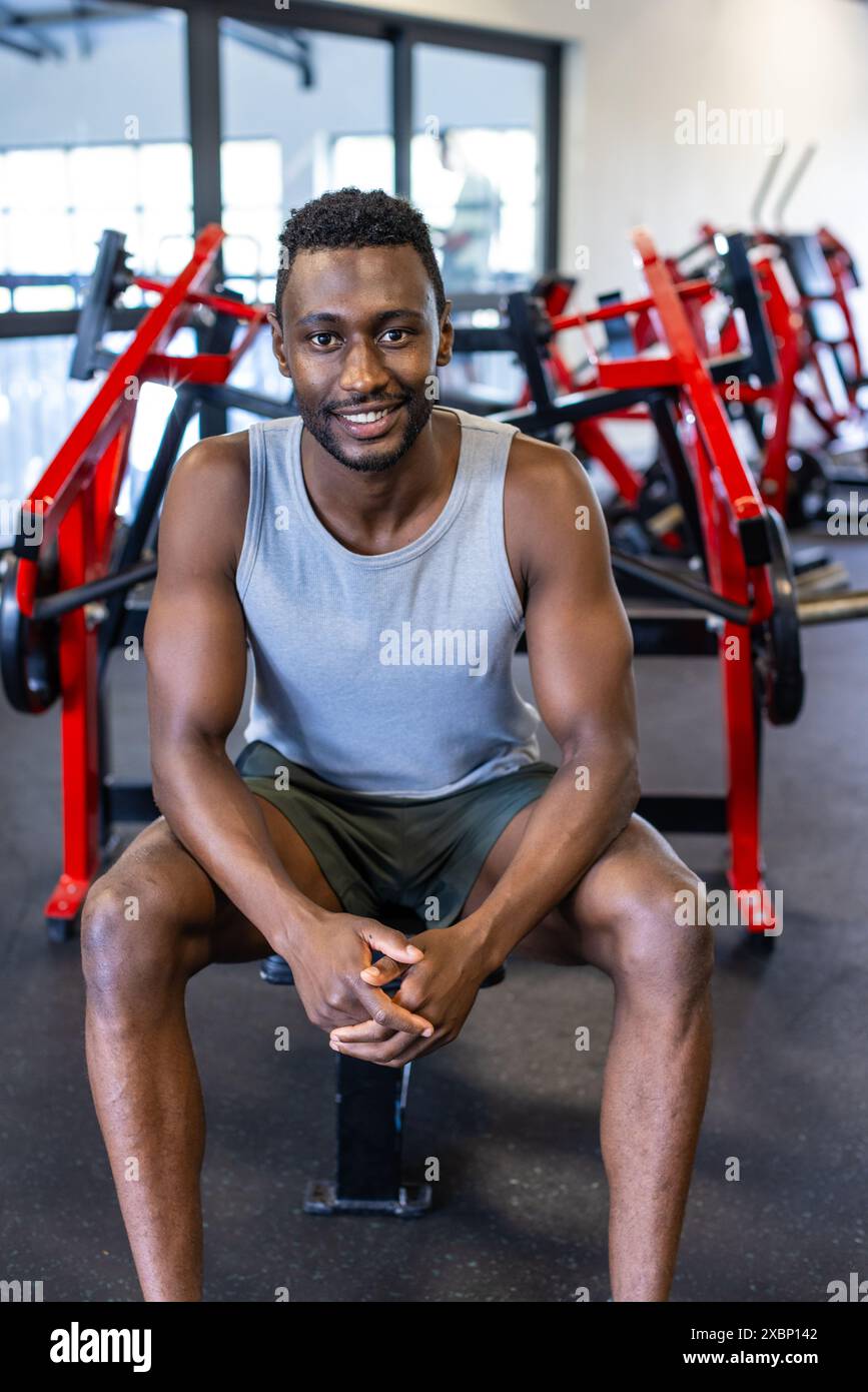 Strong African American man sits on gym bench, smiling confidently ...