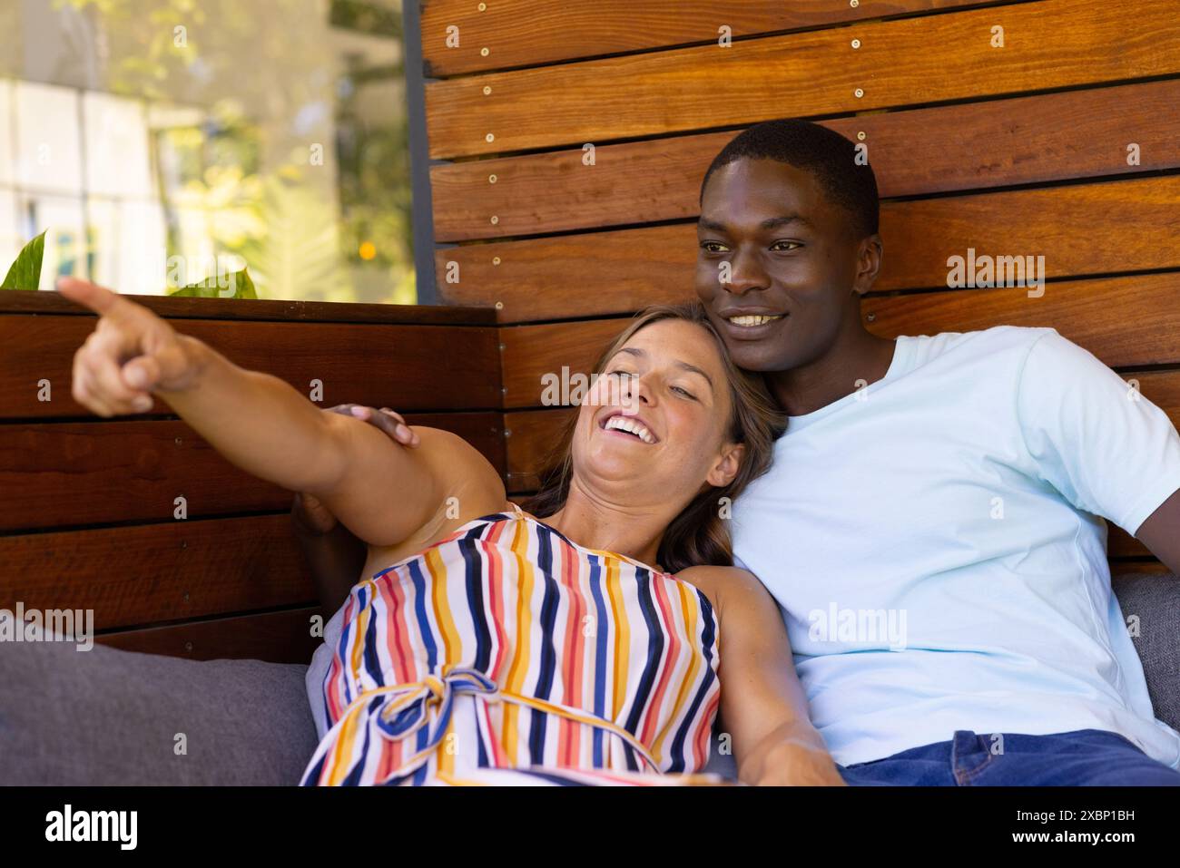 A diverse couple relaxes together, the woman pointing at something in ...