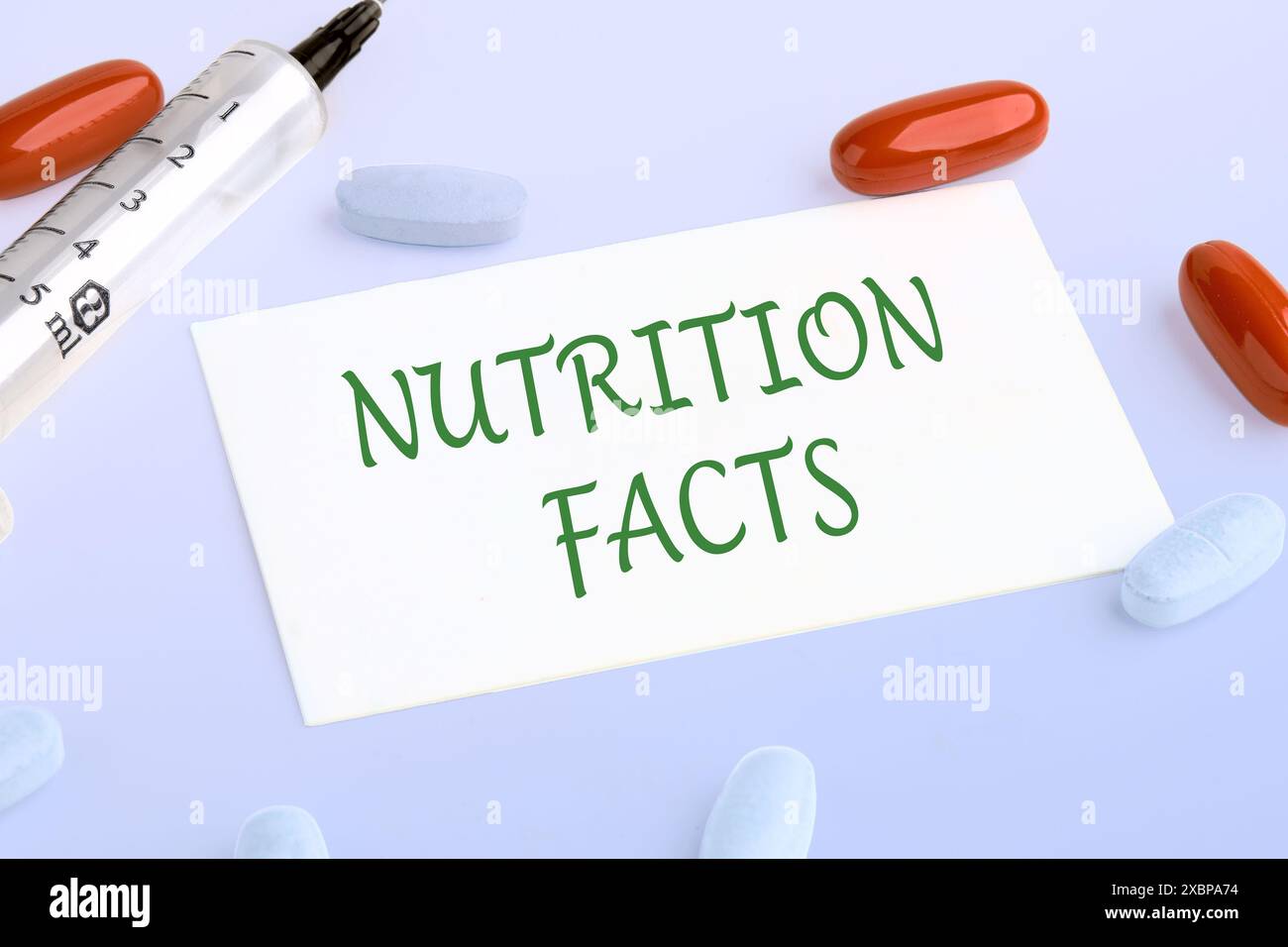 Nutrition facts text written on the business card next to pills ...