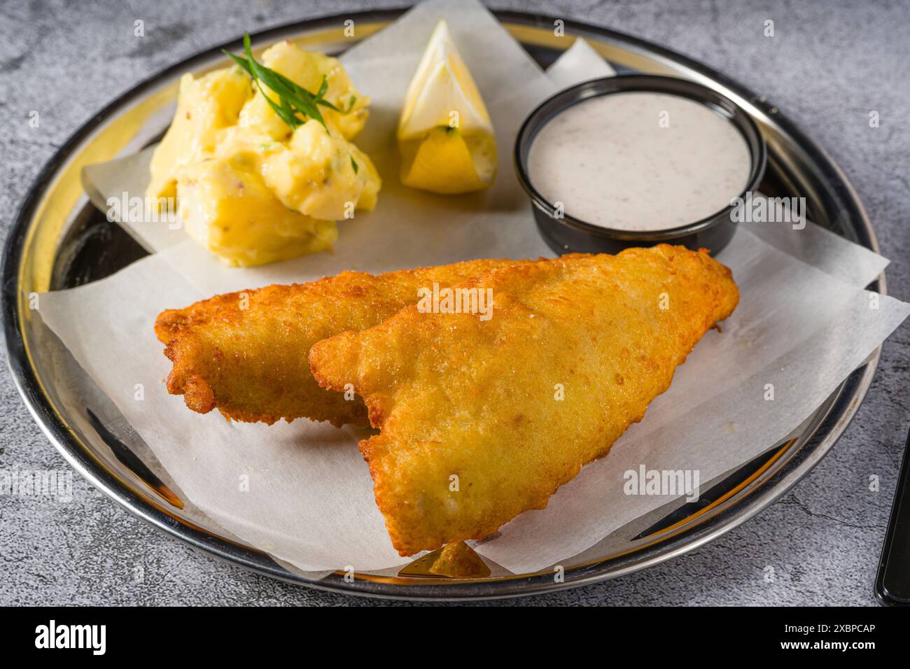 Deep fried coated fish fillet with potato salad on stone table Stock ...