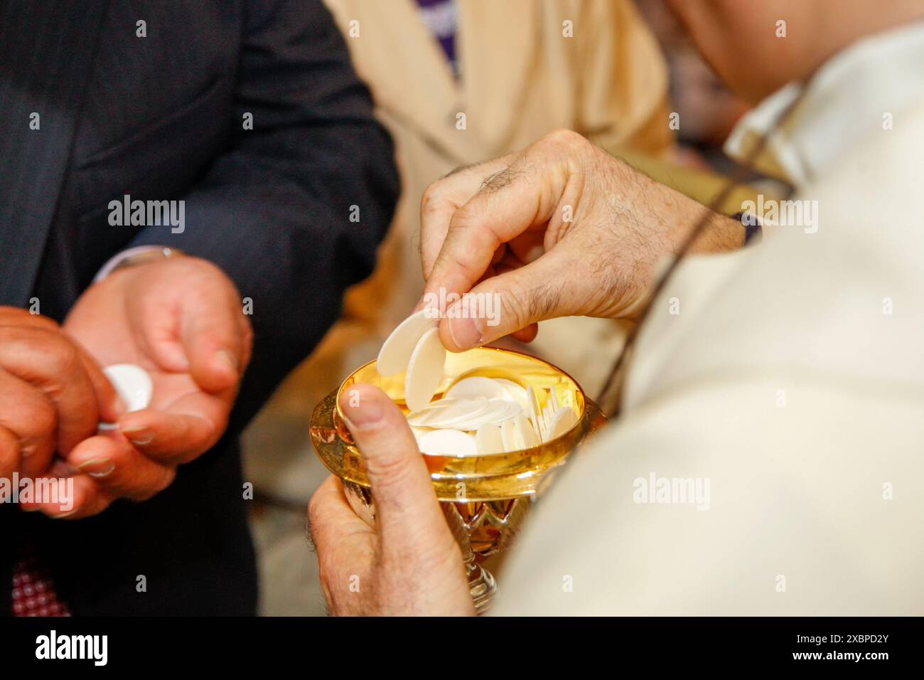 Priest holding a golden chalice with consecrated hosts during the ...
